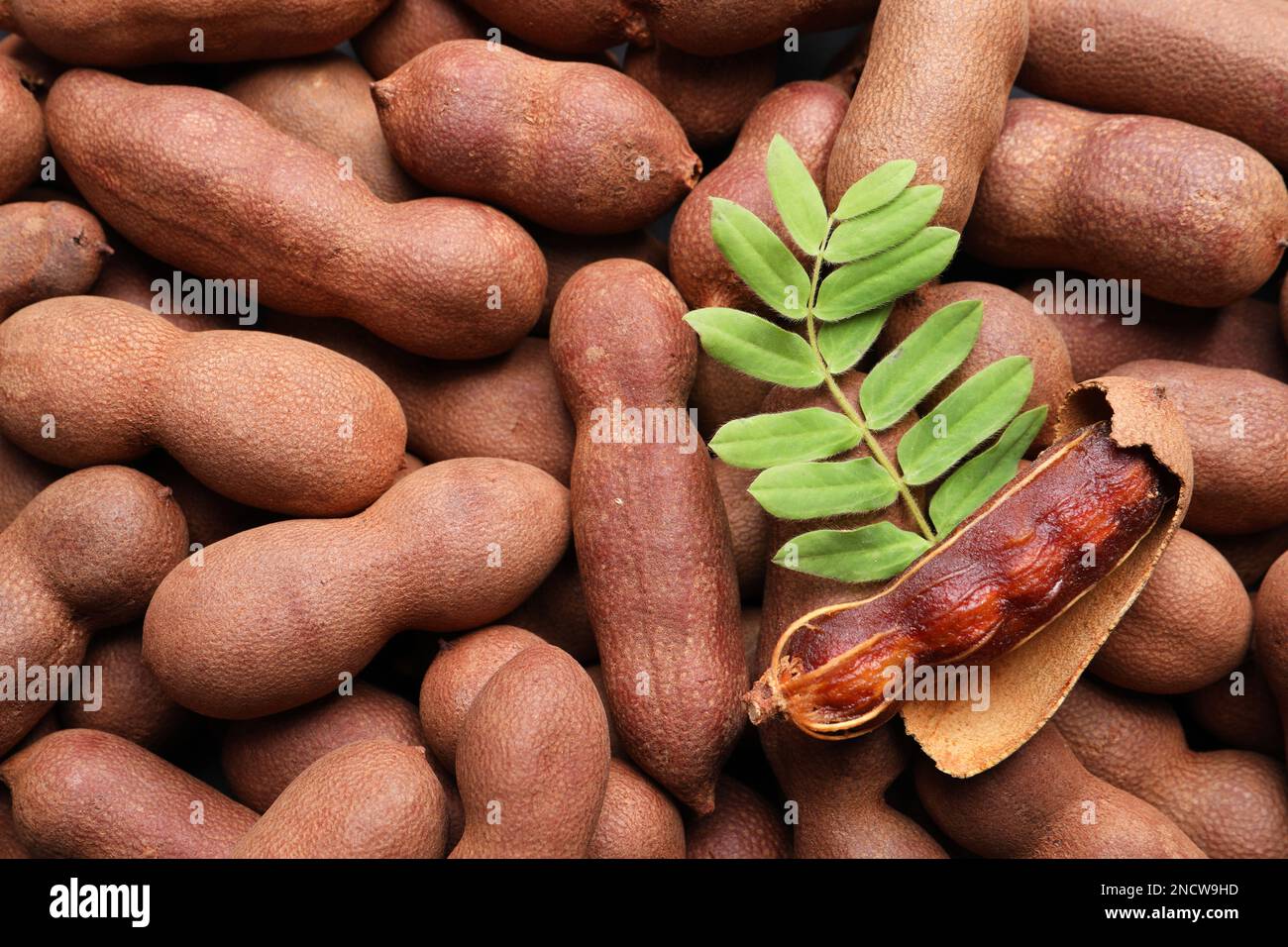 Delicious ripe tamarinds with leaves as background, closeup. Exotic ...