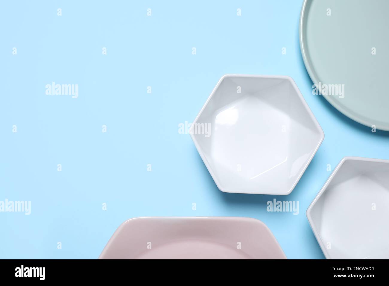 Set of ceramic dishware on light blue background, flat lay. Space for ...