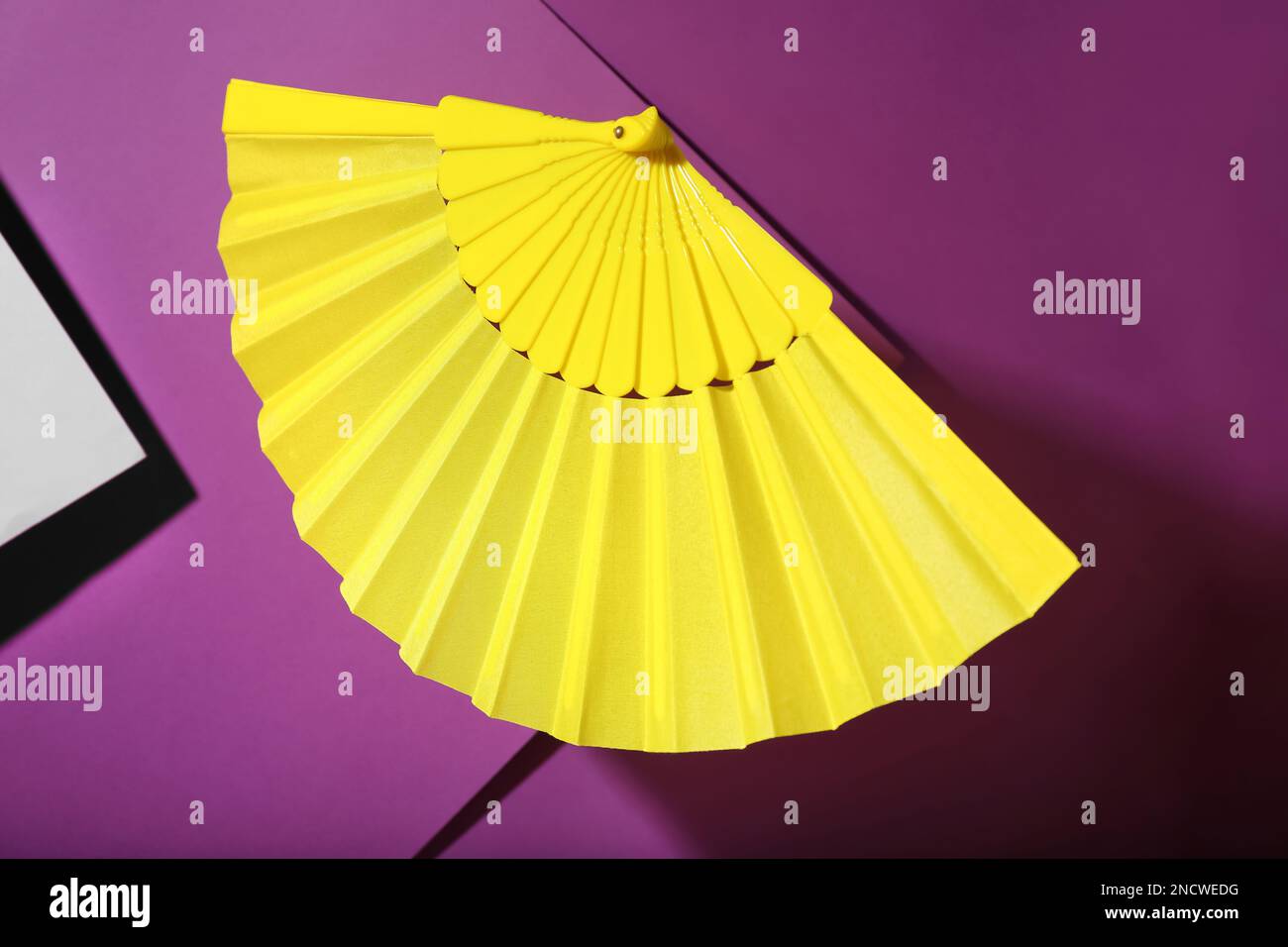 Folding yellow hand fan on purple background Stock Photo - Alamy