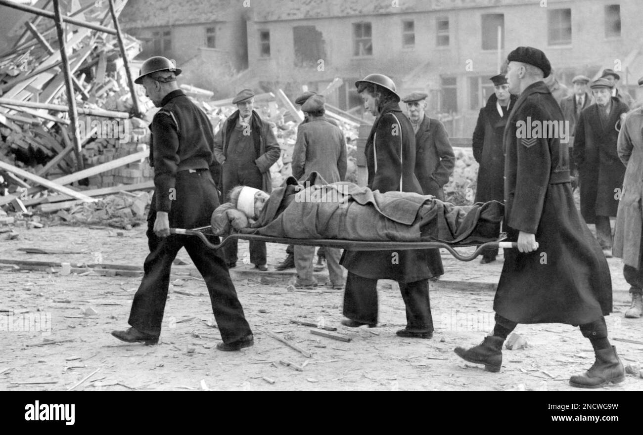 A wounded London woman is carried away from the ruins of her home which ...