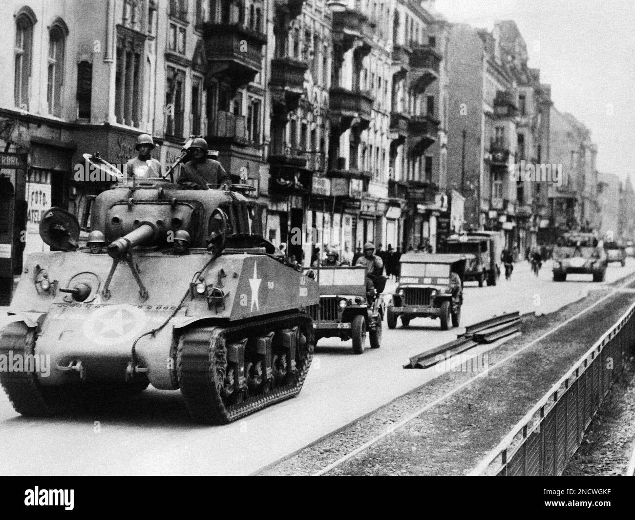 A general Sherman tank of the American forces passes bombed out ...