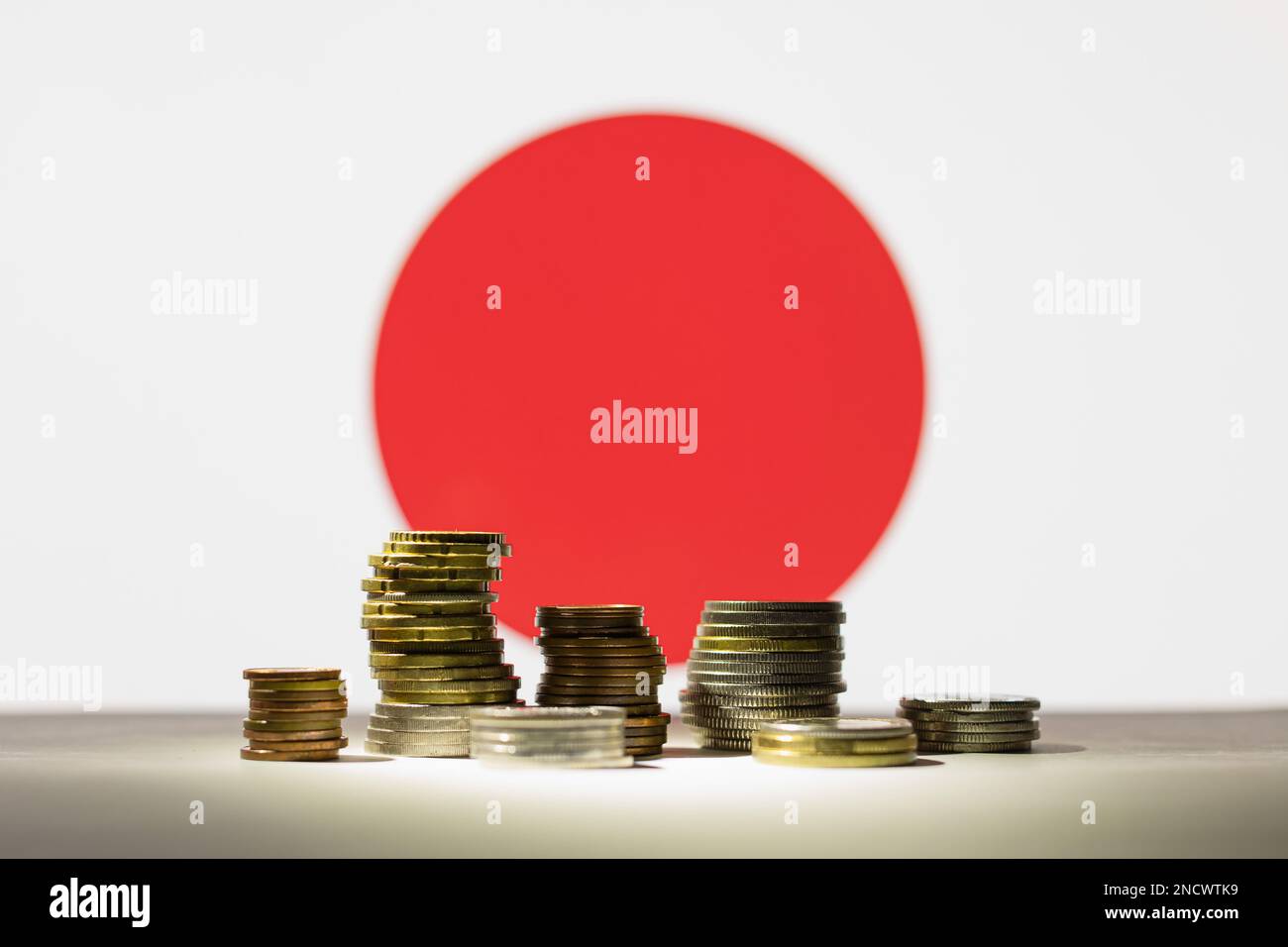 Stacked coins on a white table and a Japan flag in a background Stock ...