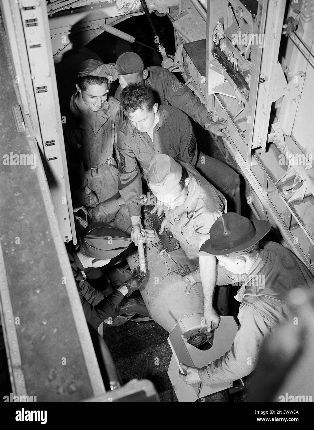 Seen through the bomb doors, the ground crews get ready to hoist a big ...