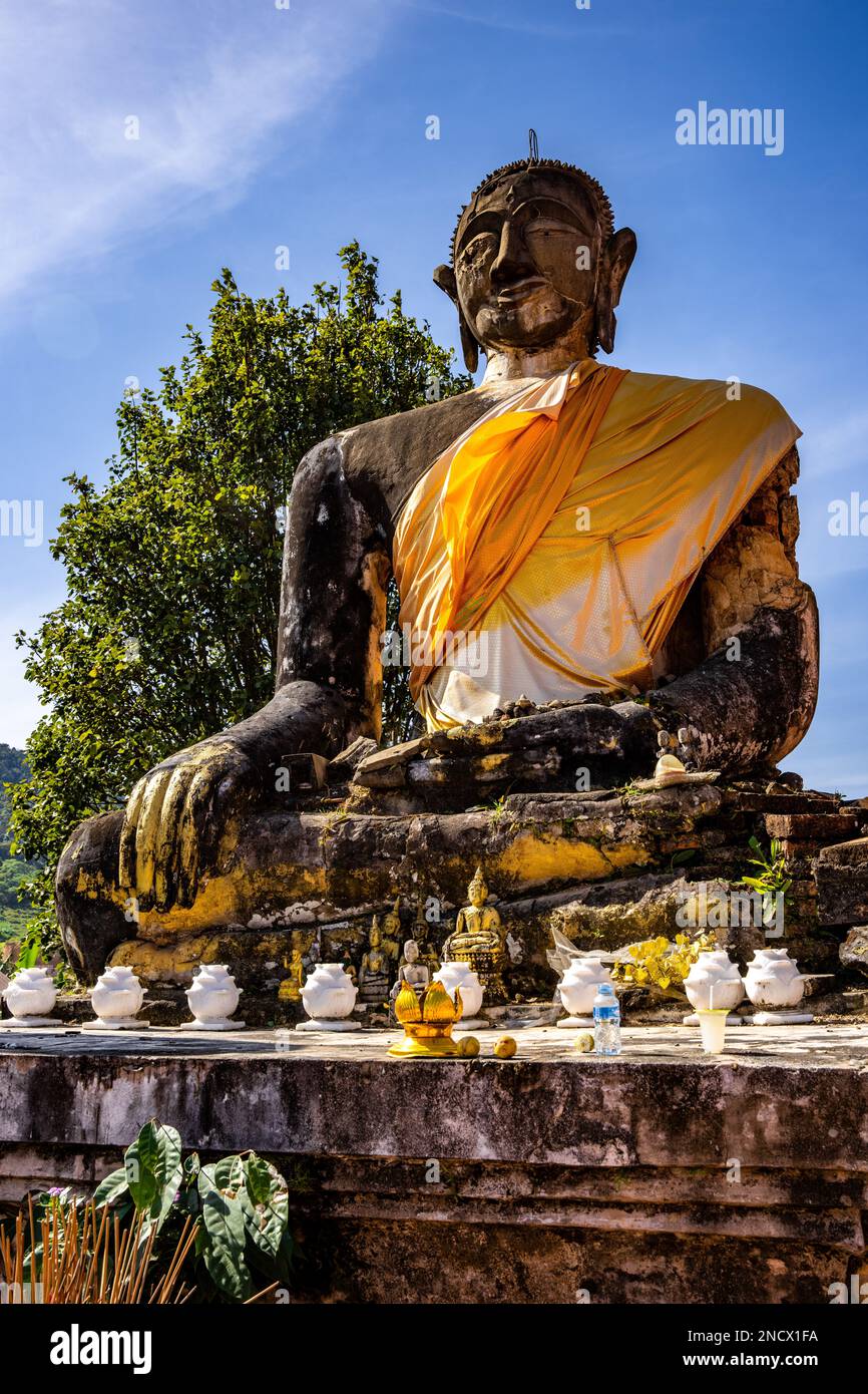 A vertical shot of an ancient and worn statue of Buddha in Wat Phiawat ...