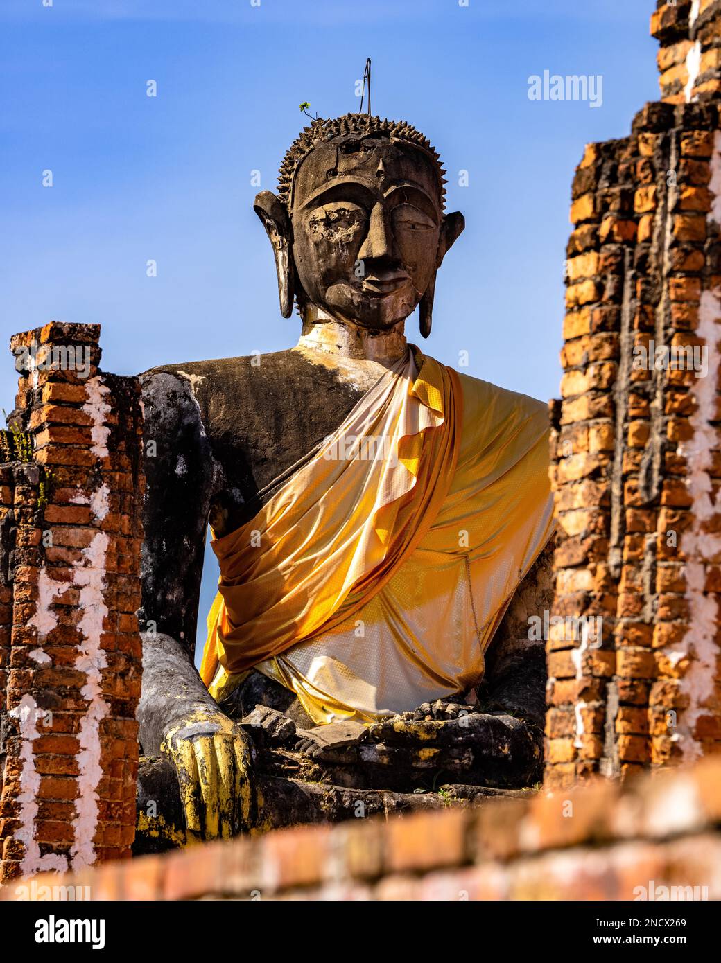 A vertical shot of an ancient and worn statue of Buddha in Wat Phiawat ...