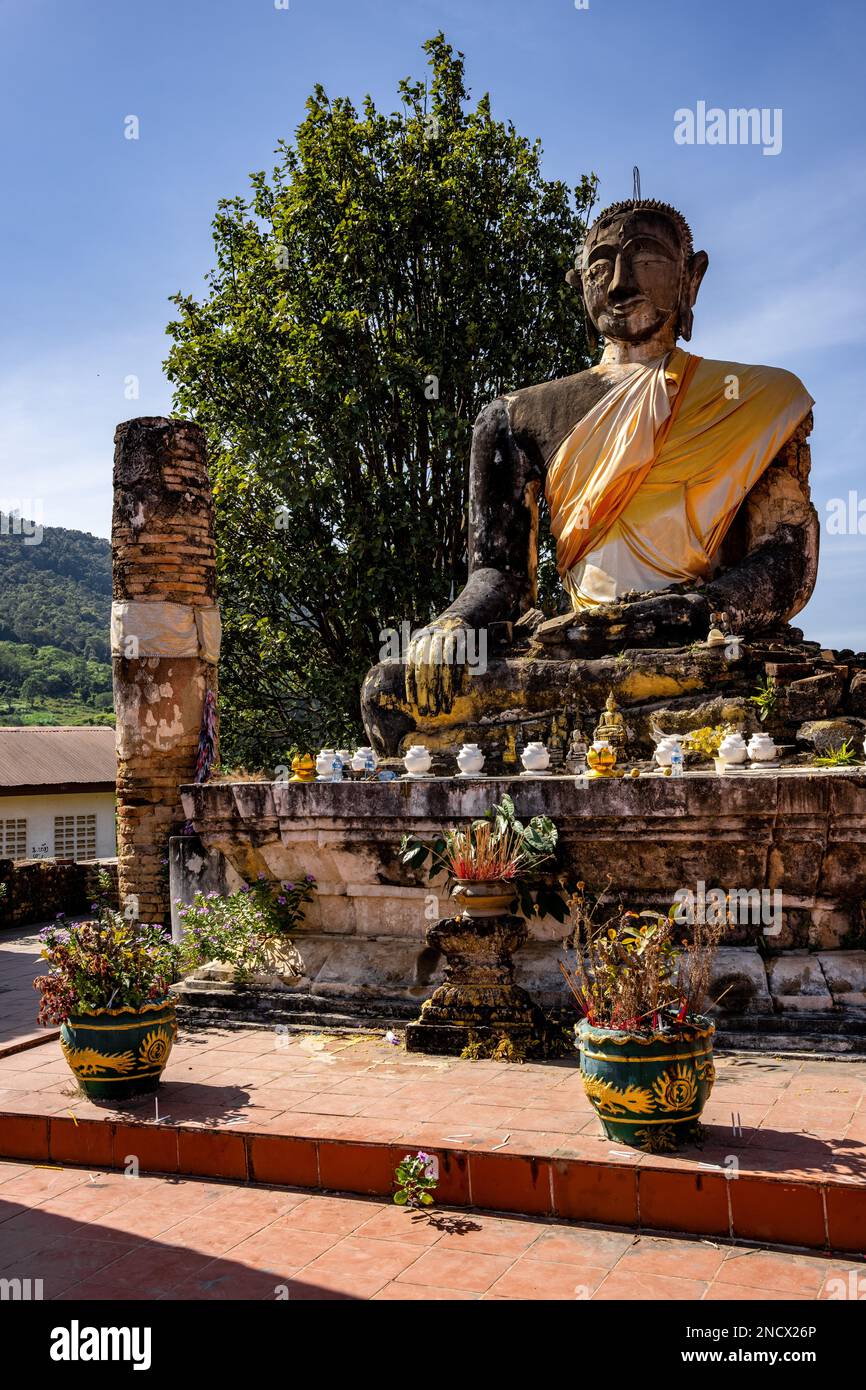 A vertical shot of an ancient and worn statue of Buddha in Wat Phiawat ...