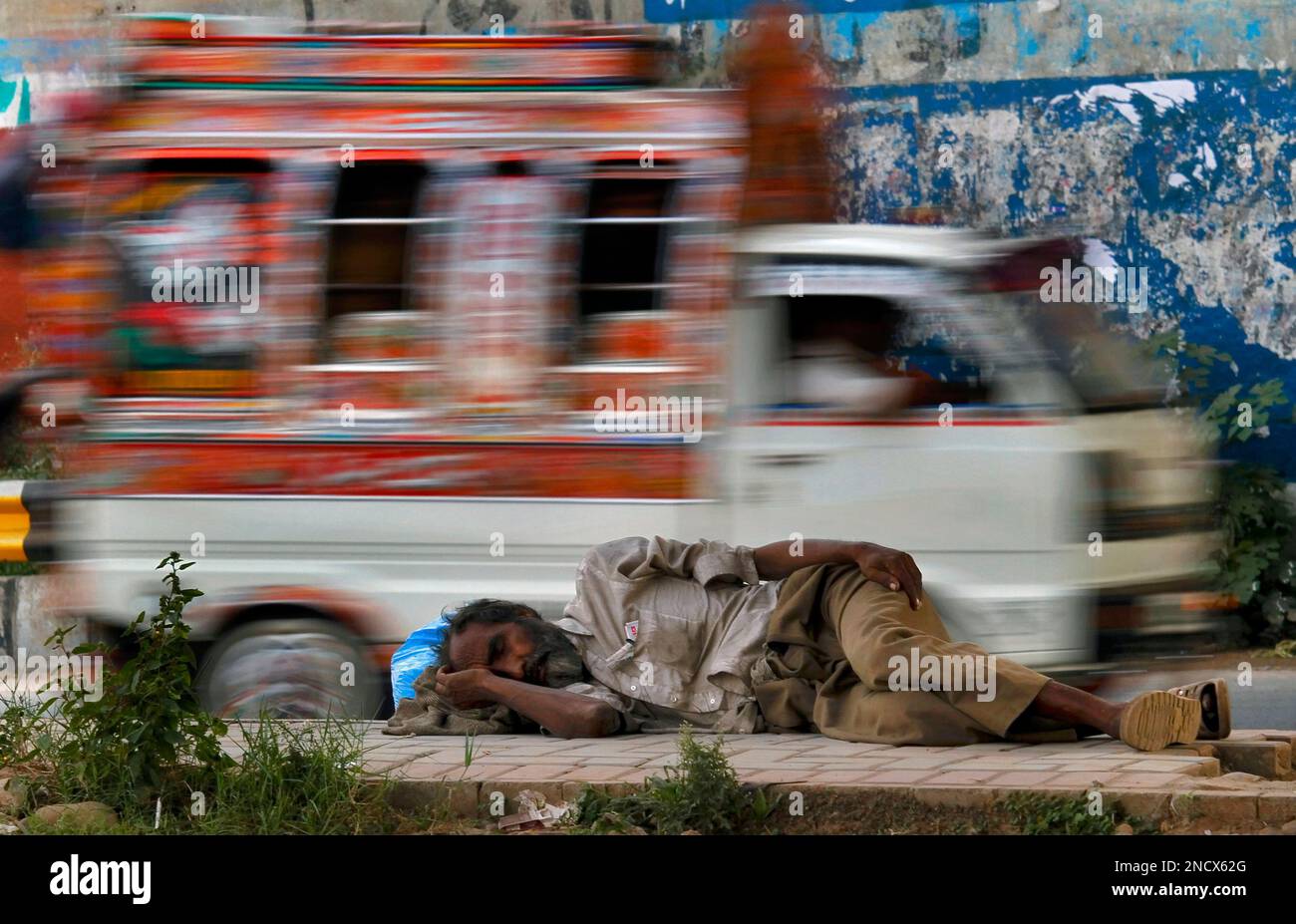 A homeless Pakistani sleeps on the footpath under a bridge at a road on ...