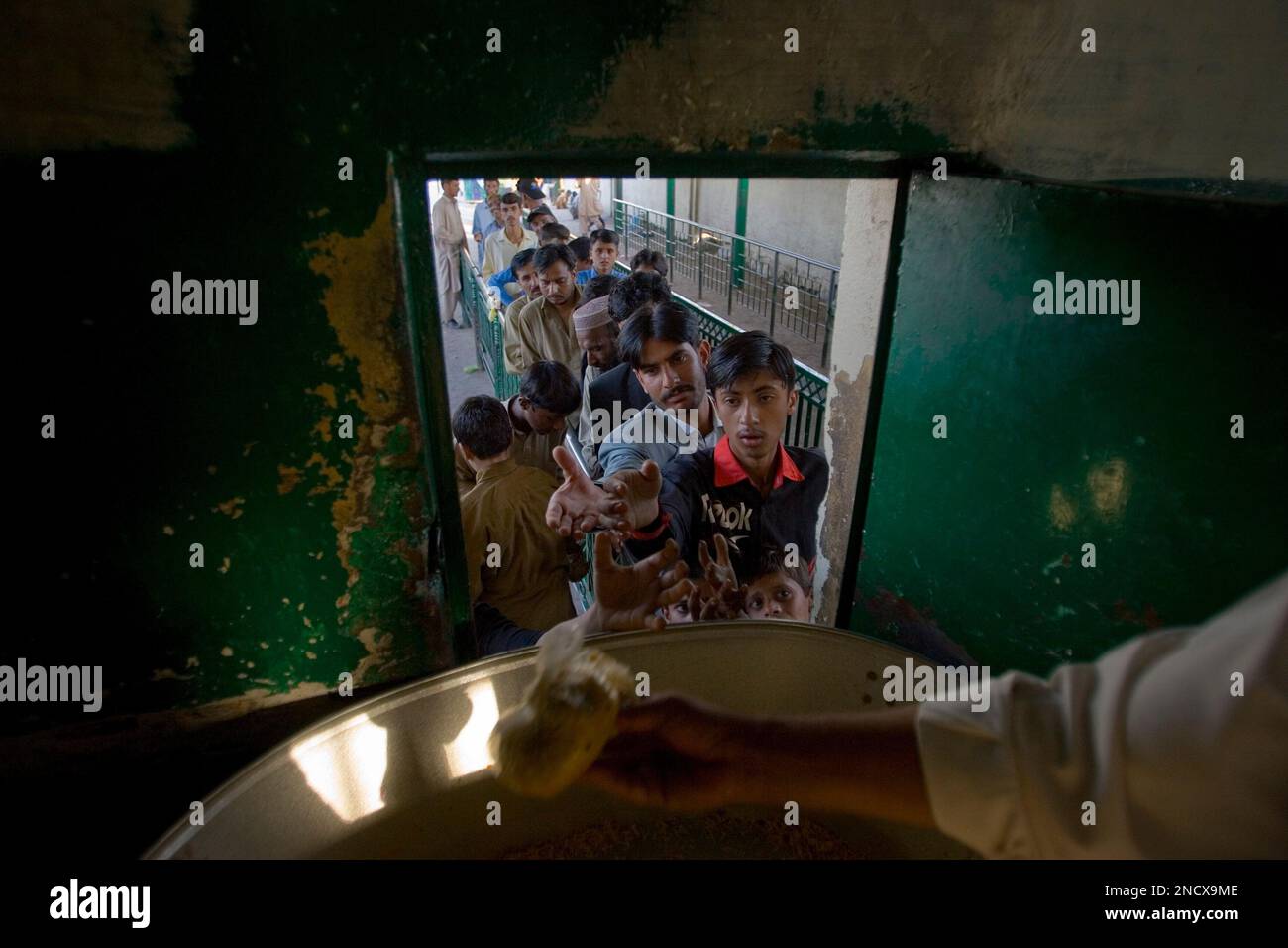 Pakistanis gets free food from a food distribution point at the shrine ...