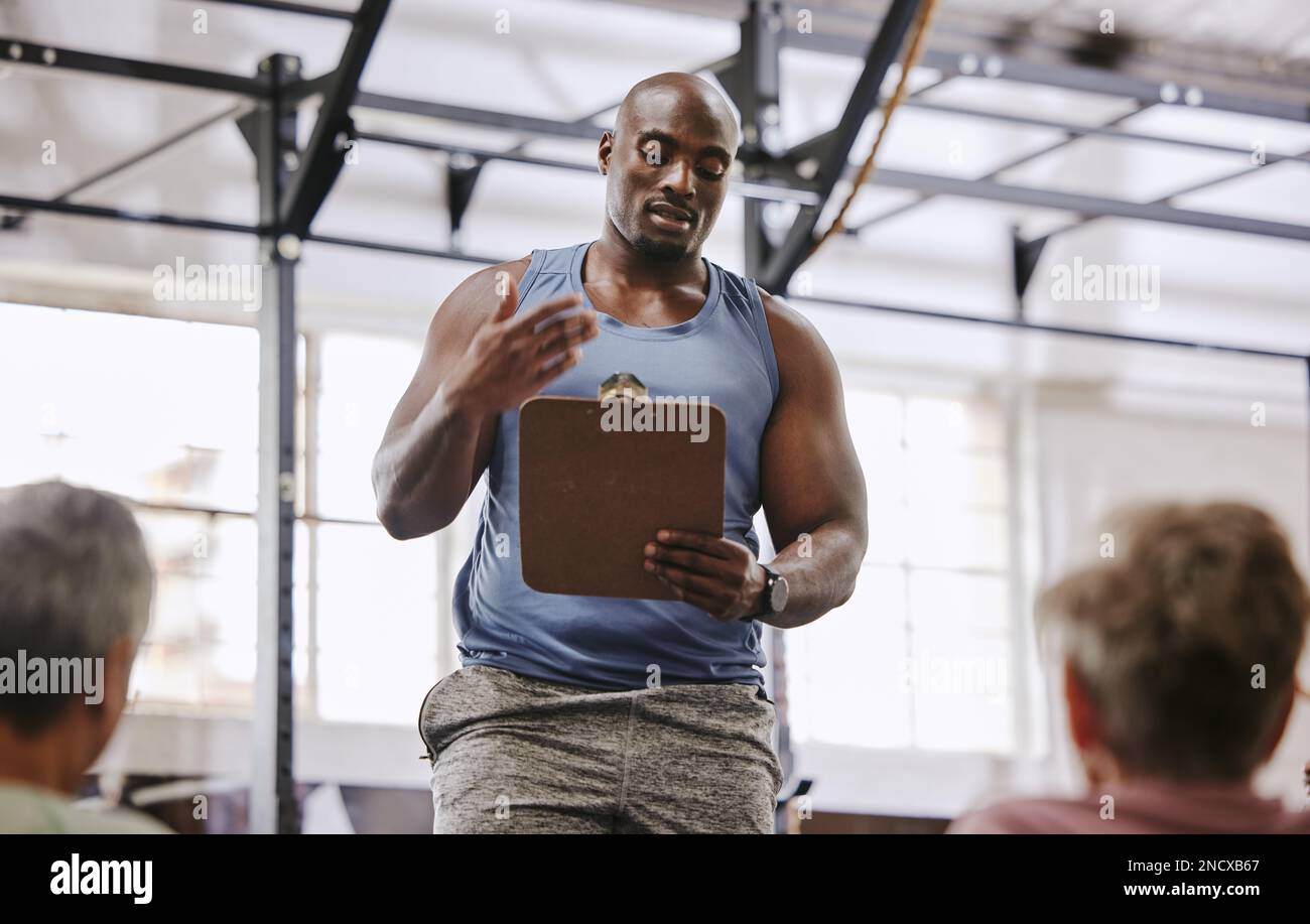 Coaching, gym checklist and black man talking to senior clients at ...