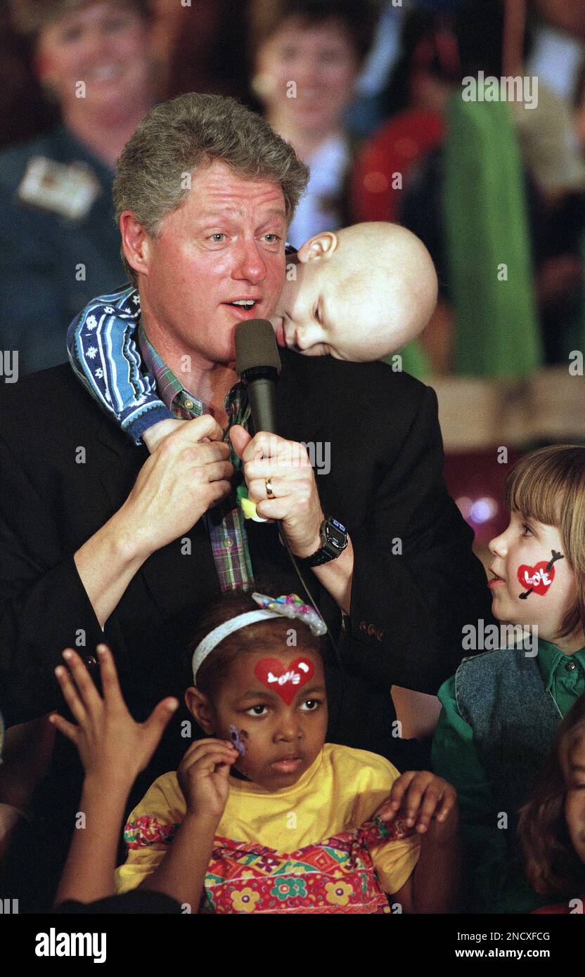 President Clinton holds the hand of 3-year-old Timothy West, who climbs ...