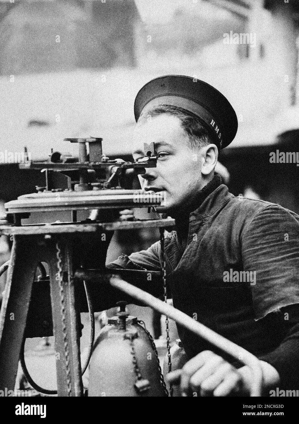 A member of the torpedo crew of H.M.S. Dorsetshire, seen taking sights ...