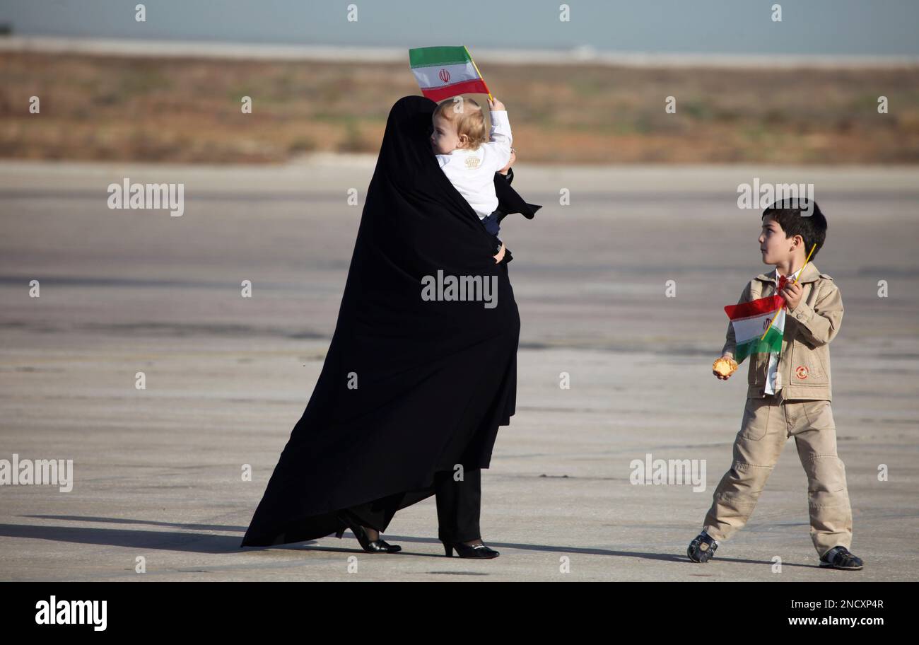 A woman and her two children carry Iranian flags as they wait for the ...