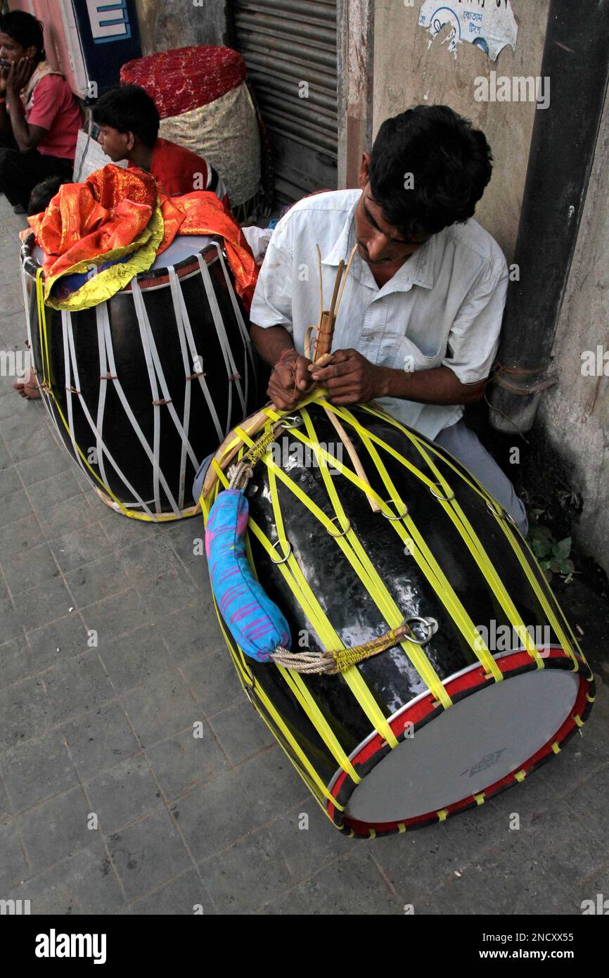 An Indian drummer tunes his drum before a performance to attract ...