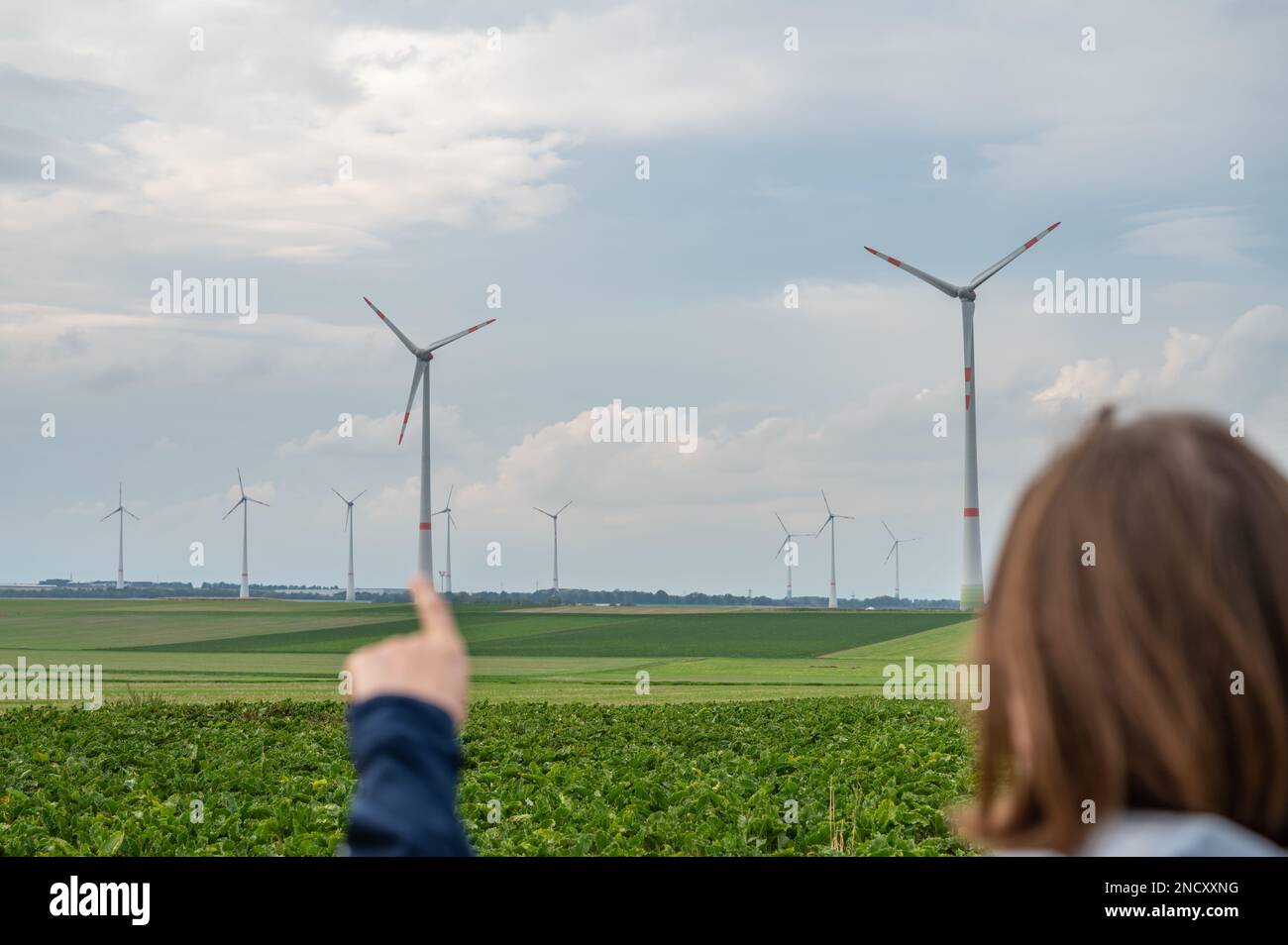Woman with brown hair and blue jacket is pointing her finger on a wind ...