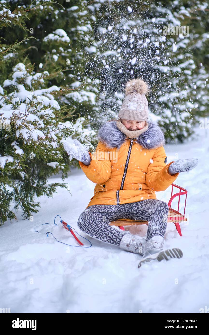 Kid girl enjoying snowy winter. Child sledding, sits on a sled and ...