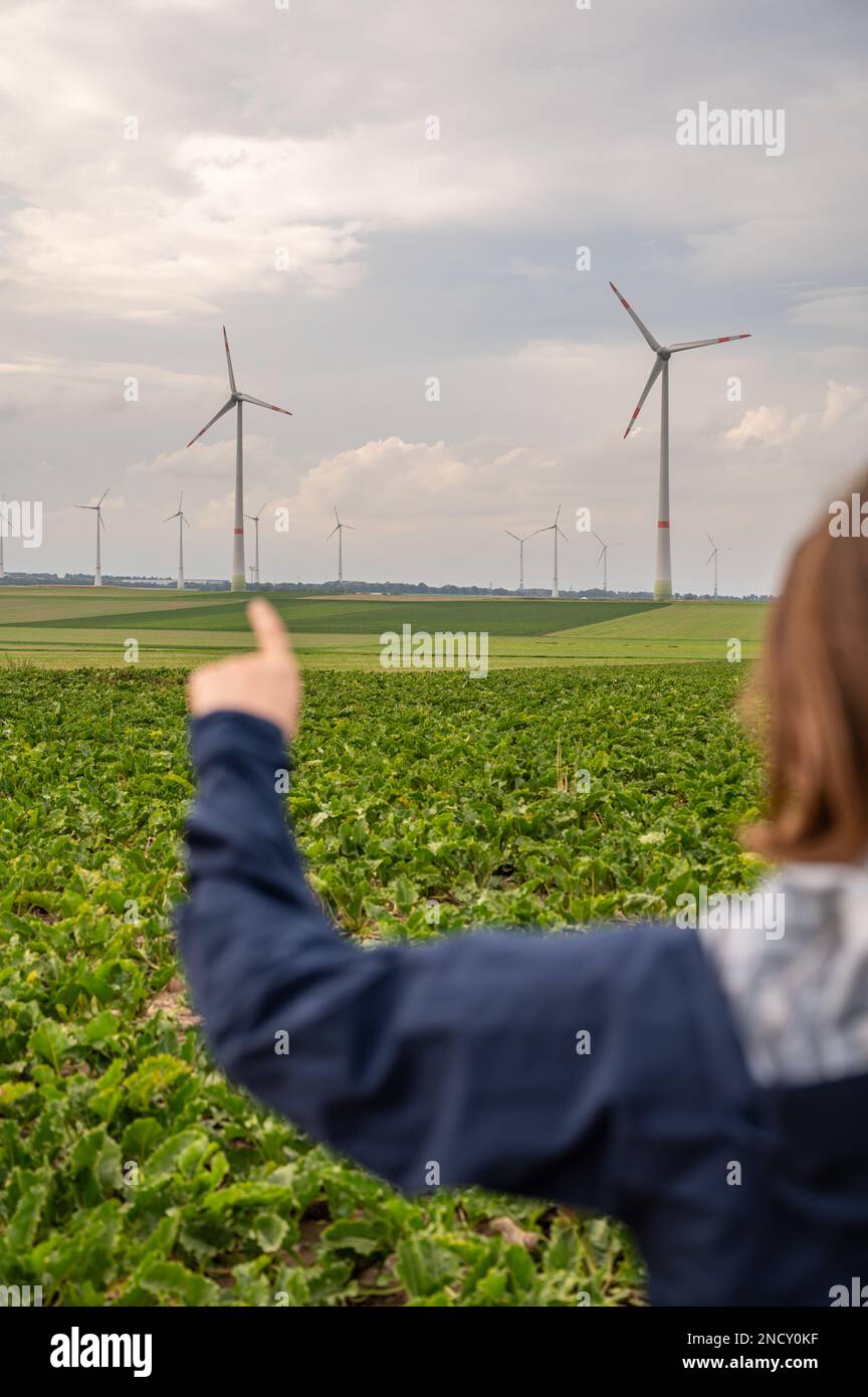 Woman with brown hair and blue jacket is pointing her finger on a wind ...