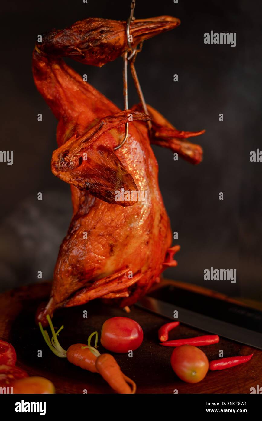 Close-up of a traditional Asian Peking duck hanging over vegetables a ...