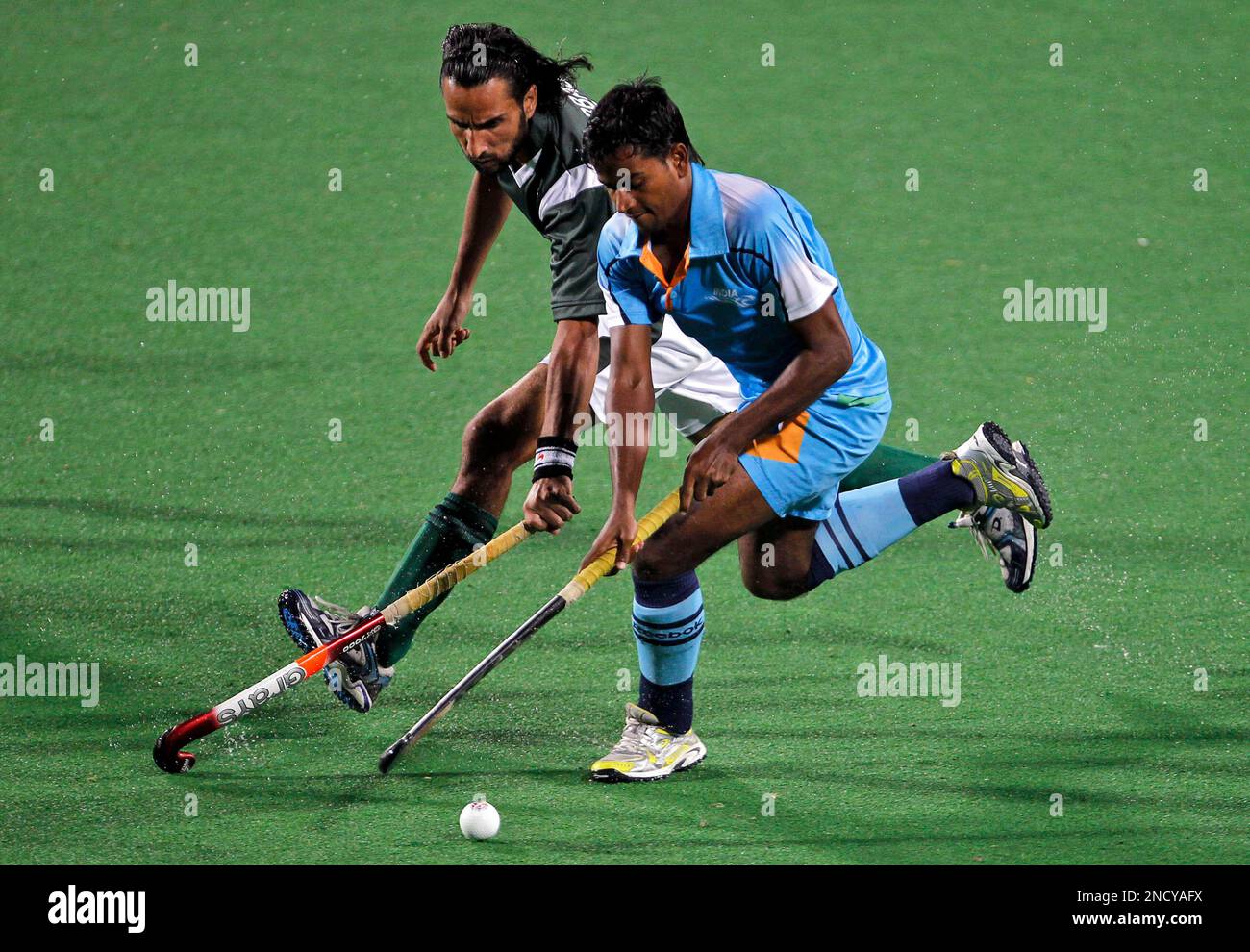 Pakistan's hockey player Shakeel Abbasi, in green, tries to stop India ...