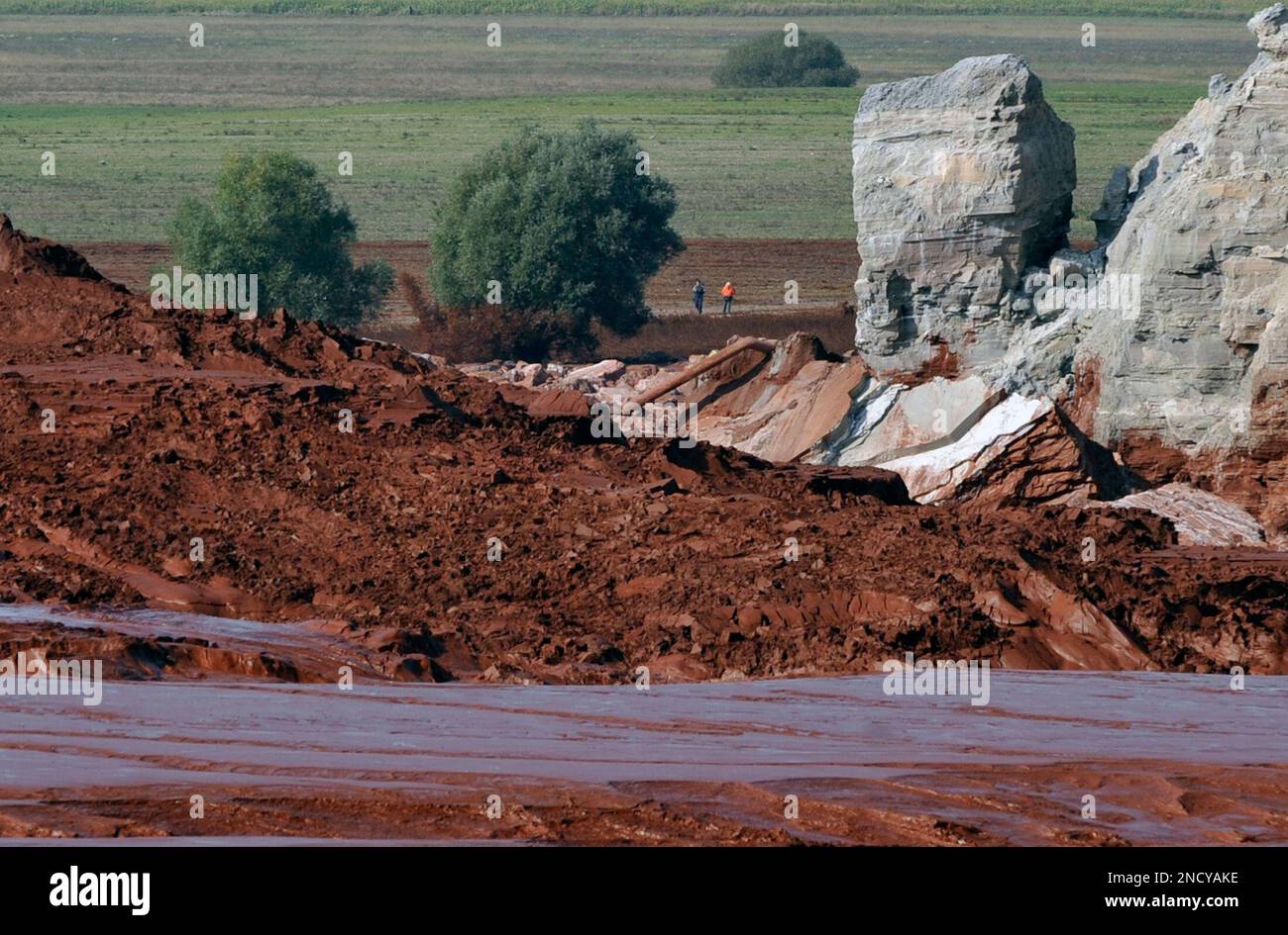 People walk behind the rupture of a reservoir, which caused the flood ...