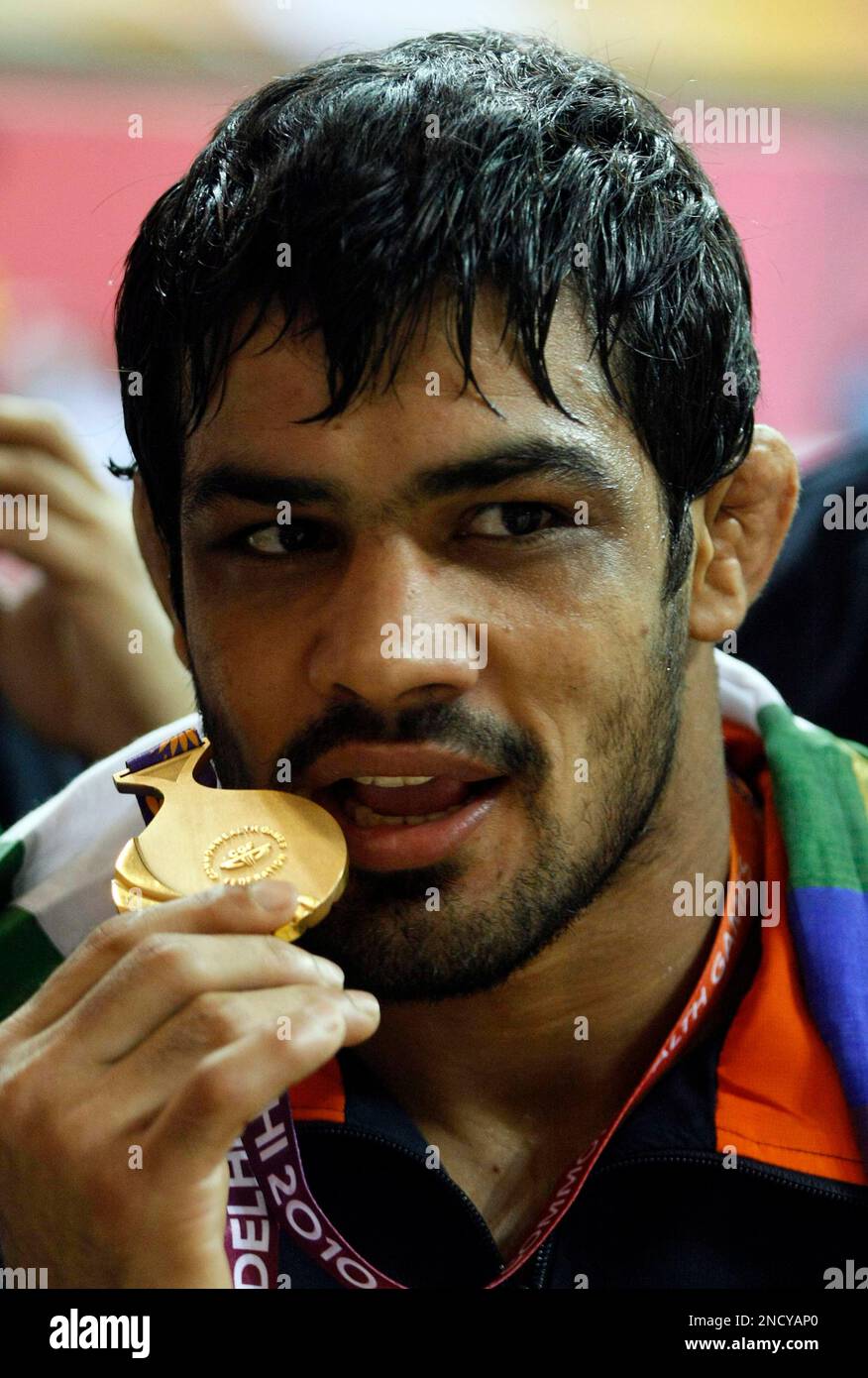 India's Sushil Kumar bites his gold medal for the 66 kilogram men's ...