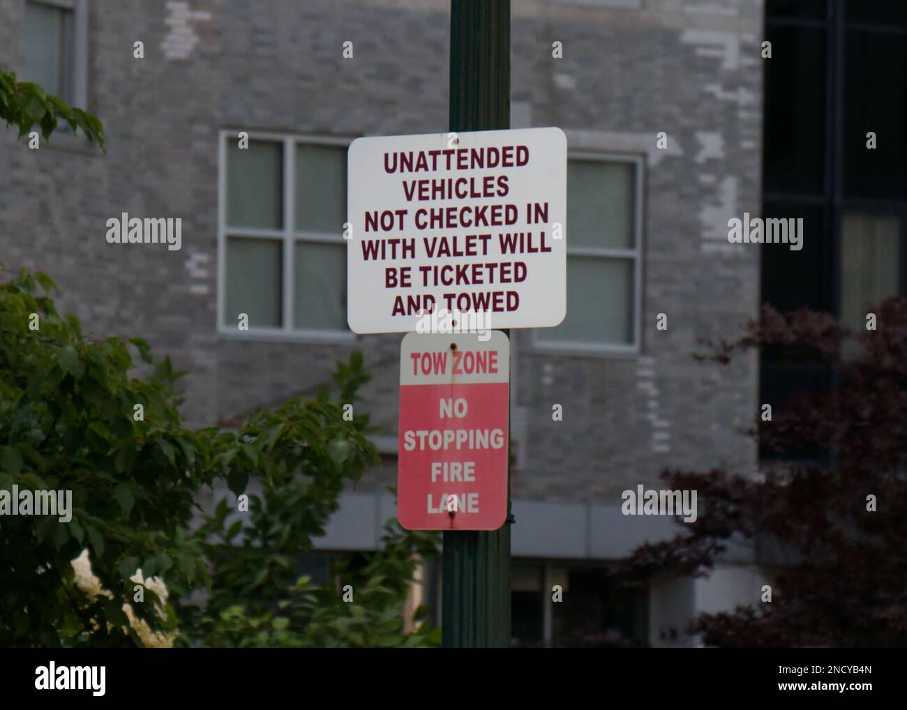 A closeup of a warning board on an iron pole with building blurred ...