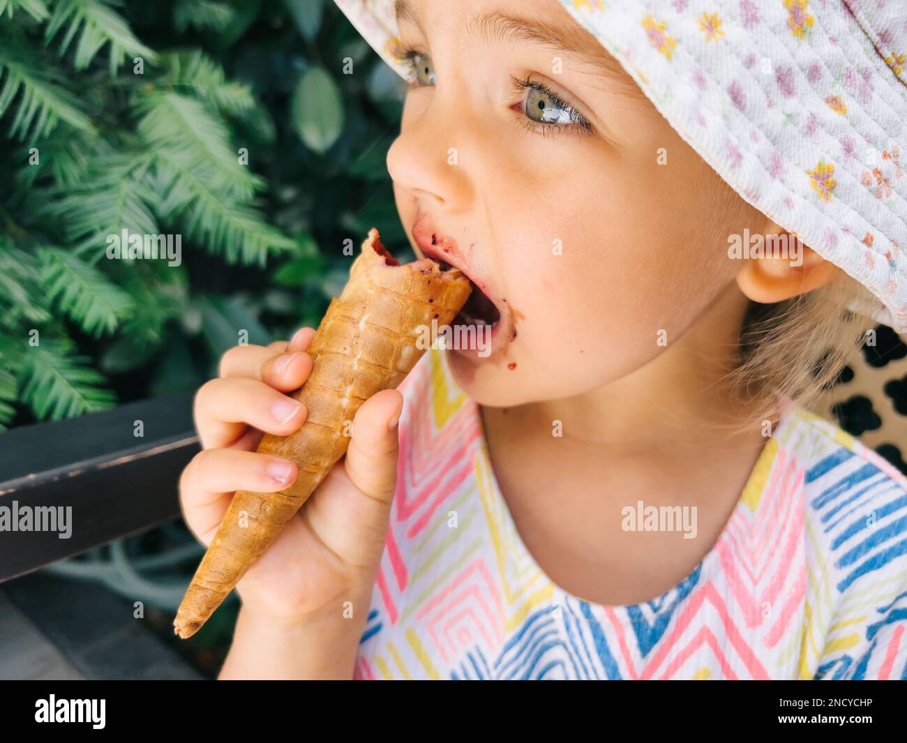 Little girl biting a popsicle in a waffle cone Stock Photo - Alamy