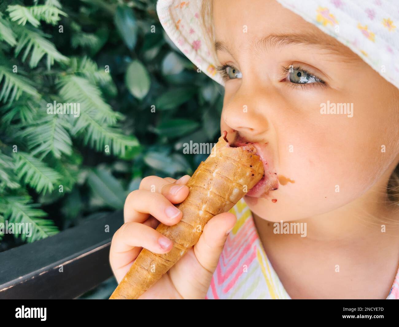 Little girl in a panama hat bites a popsicle in a waffle cone Stock ...