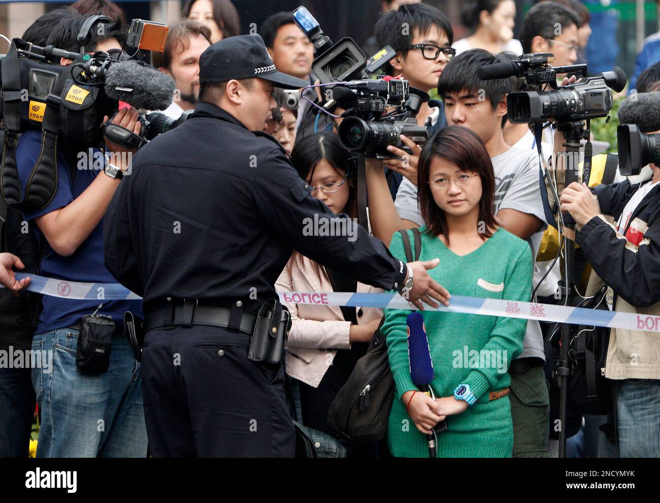 A Chinese police officer speaks to journalists as the authorities block a road entering the ...
