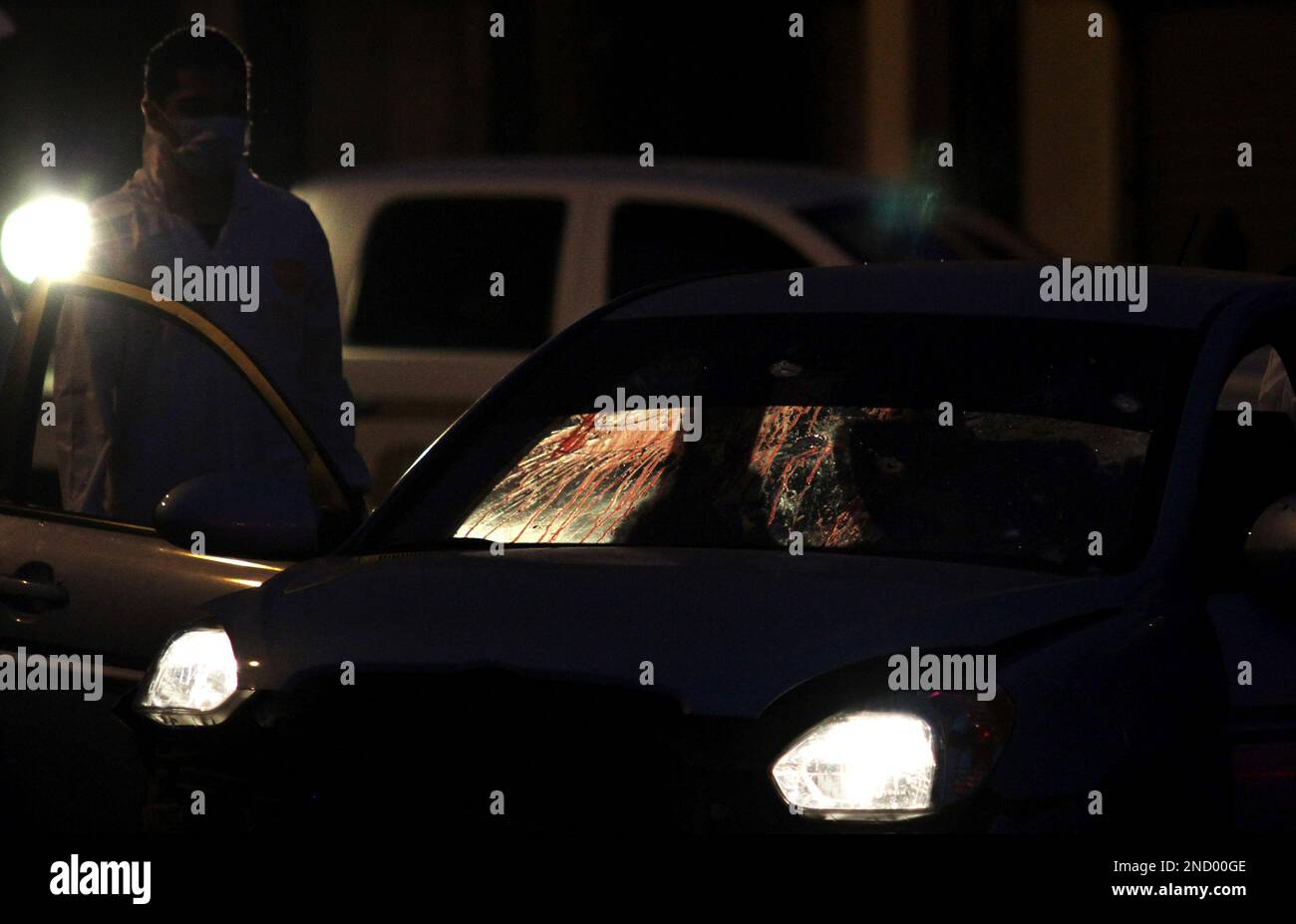 A forensic investigator approaches a blood stained and bullet ridden ...