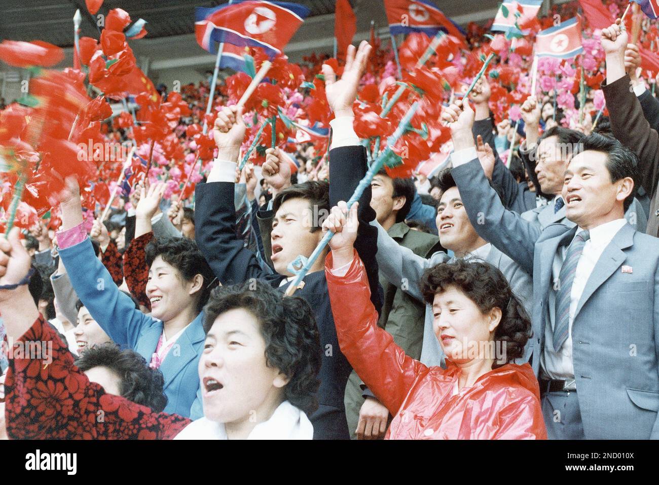 North Korean workers wave red-and-blue flags and pompoms as they pack ...
