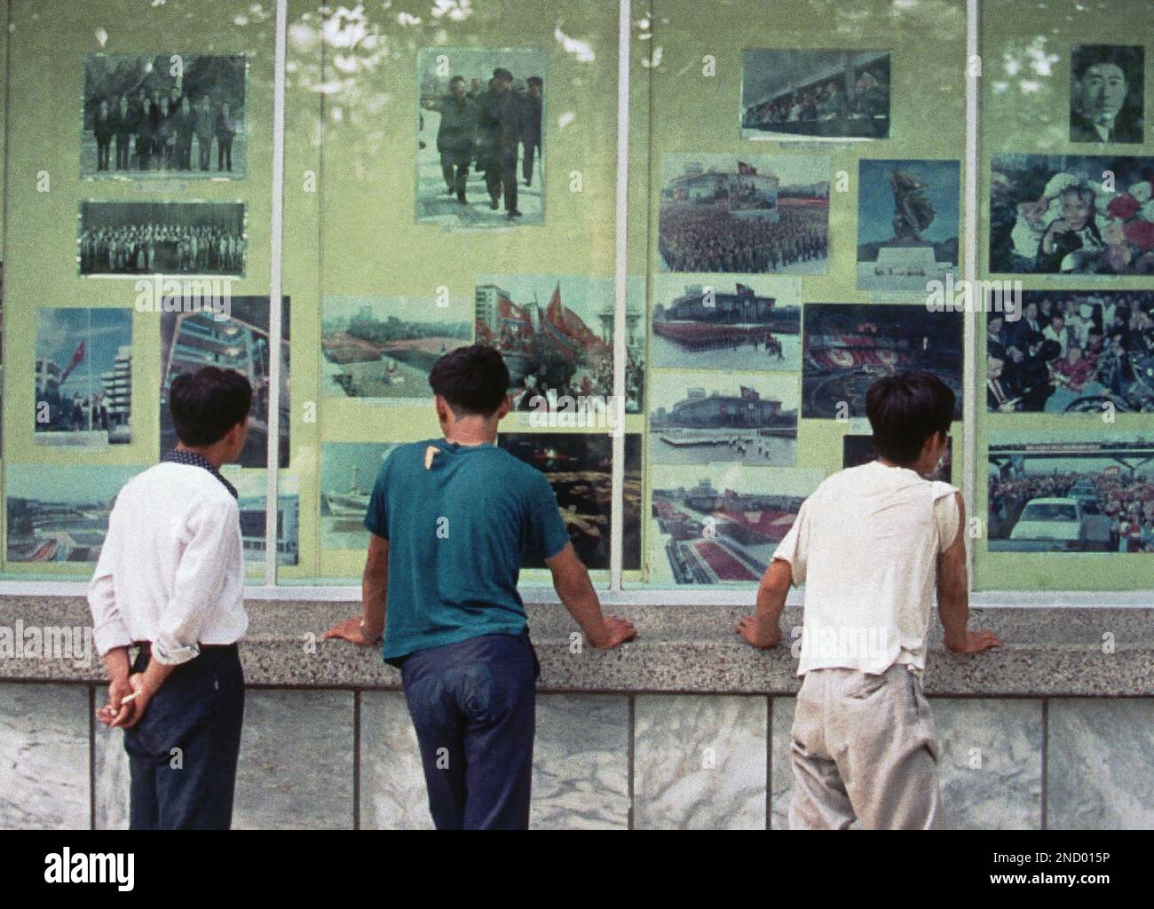 Chinese men look a display of photos showing North Korean Leader Kim II ...