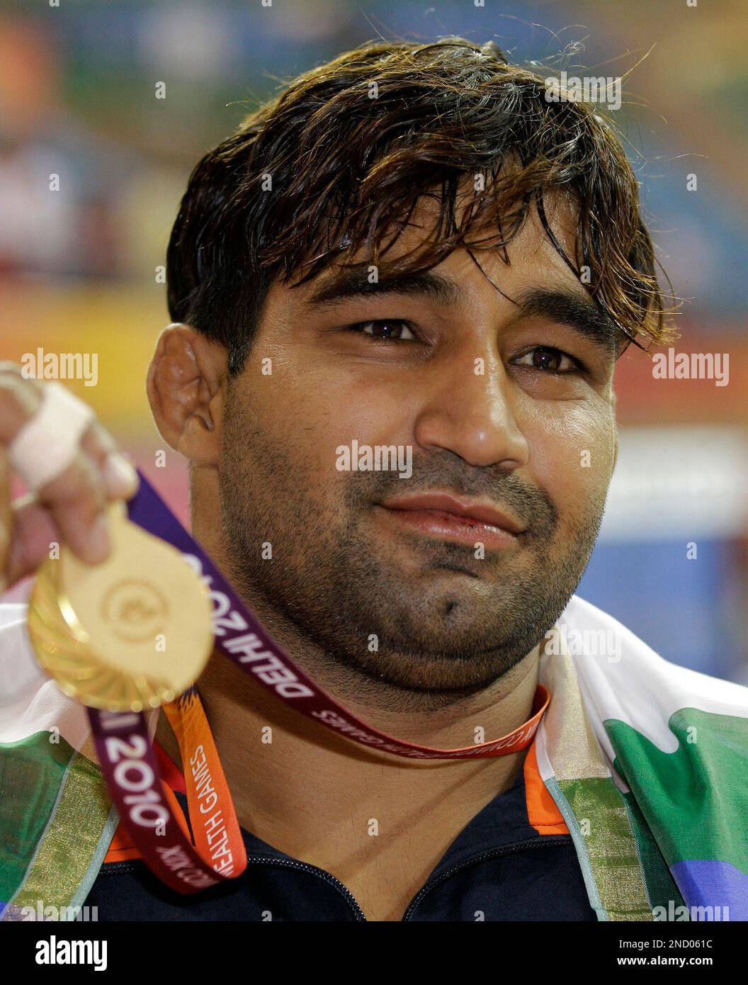 India's Anil Kumar holds his gold medal to celebrate his victory over ...