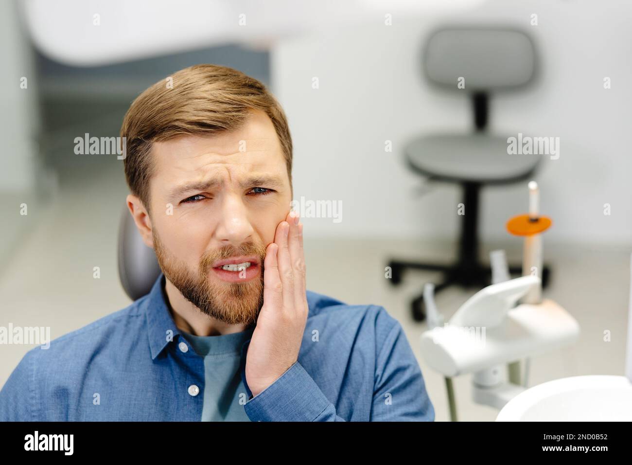 Sad man sitting in dental chair suffering from acute tooth pain ...