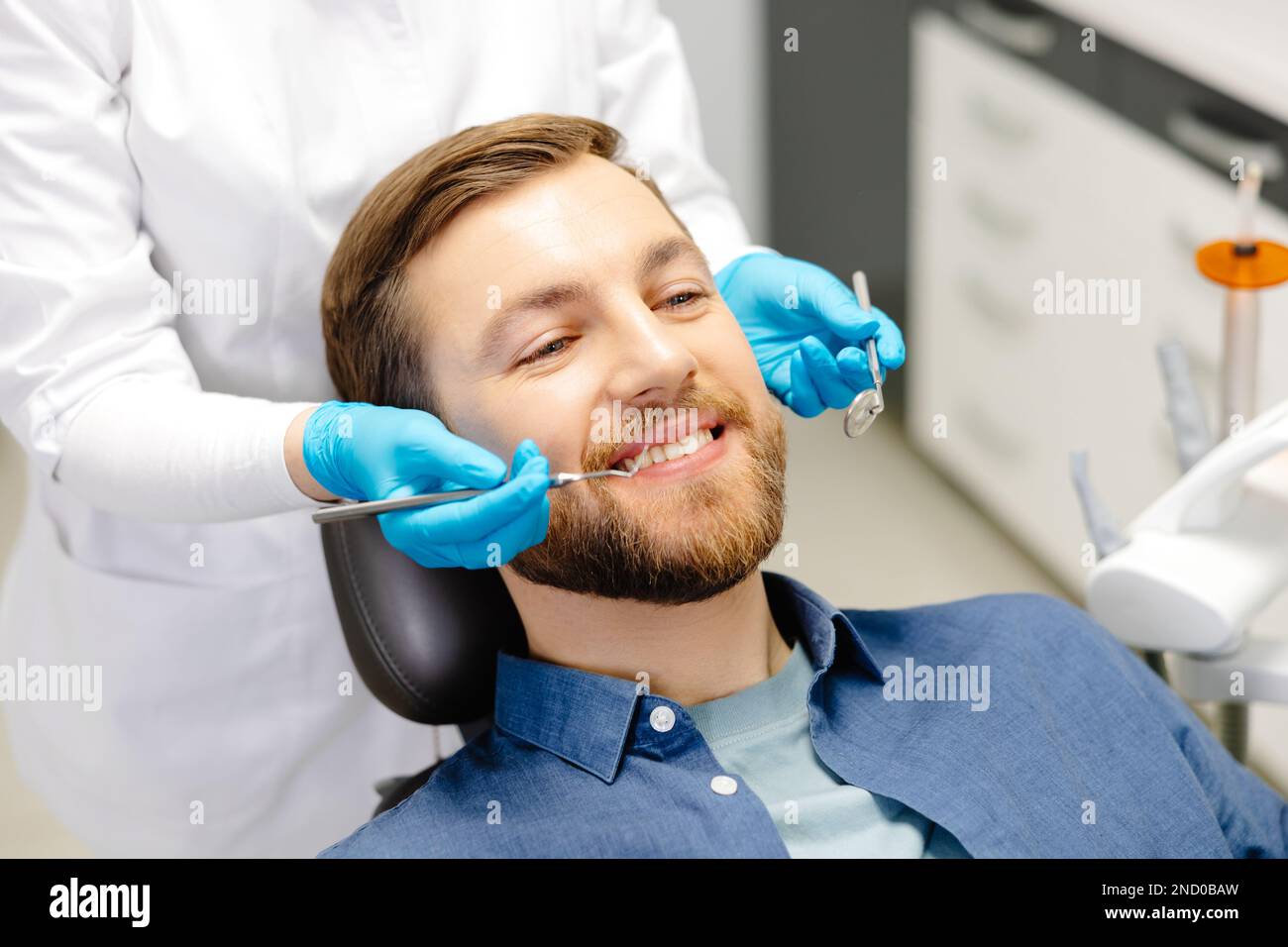 Portrait of happy man sitting at dentist chair in modern clinic and ...