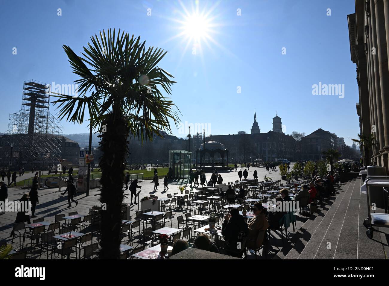 Stuttgart, Germany. 15th Feb, 2023. In bright sunshine, passers-by sit in an open-air cafe on ...