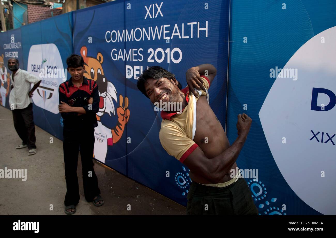 An Indian man poses for a photograph in front of boards advertising the ...