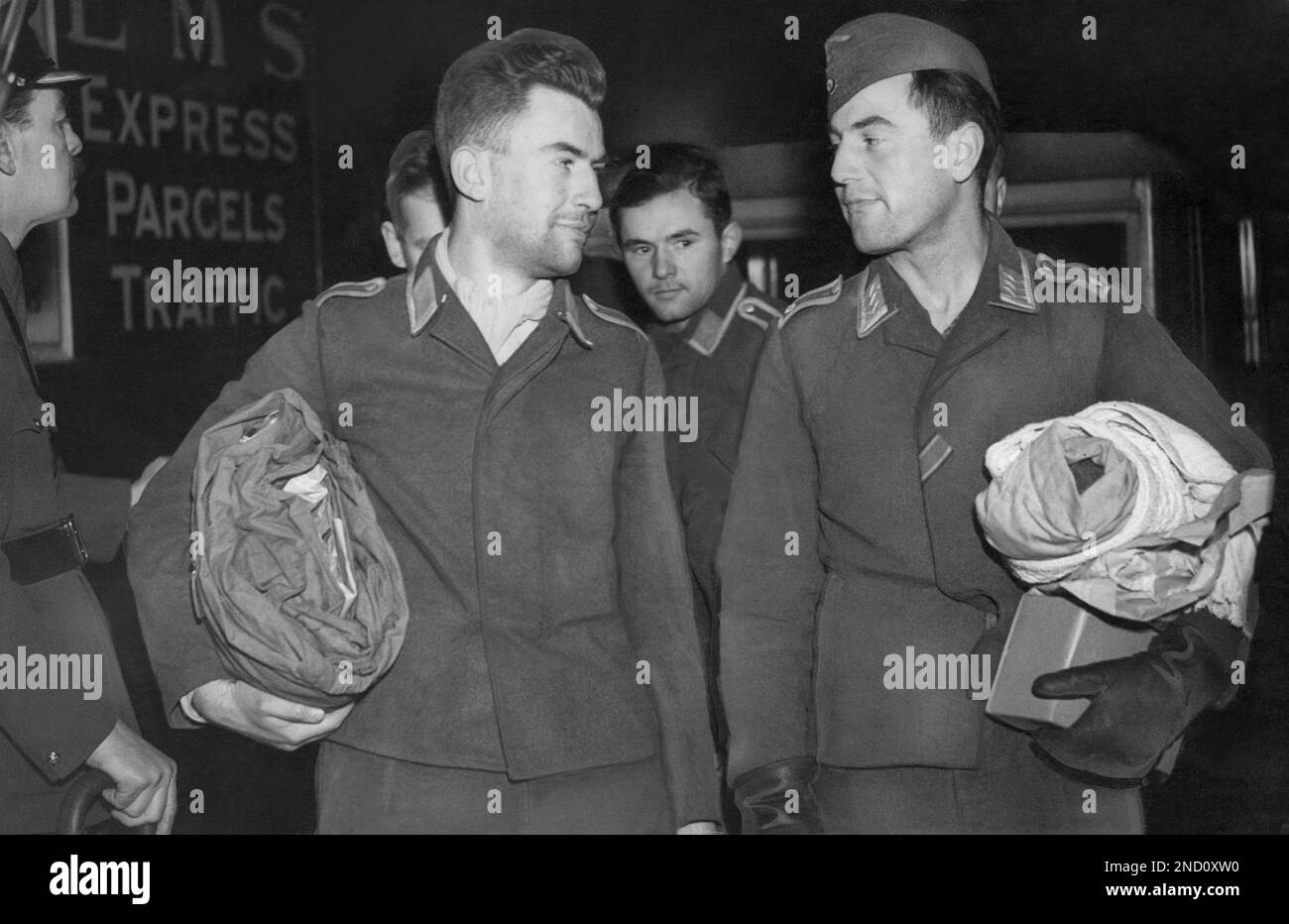 These two German prisoners of war both carrying bundles of belongings ...