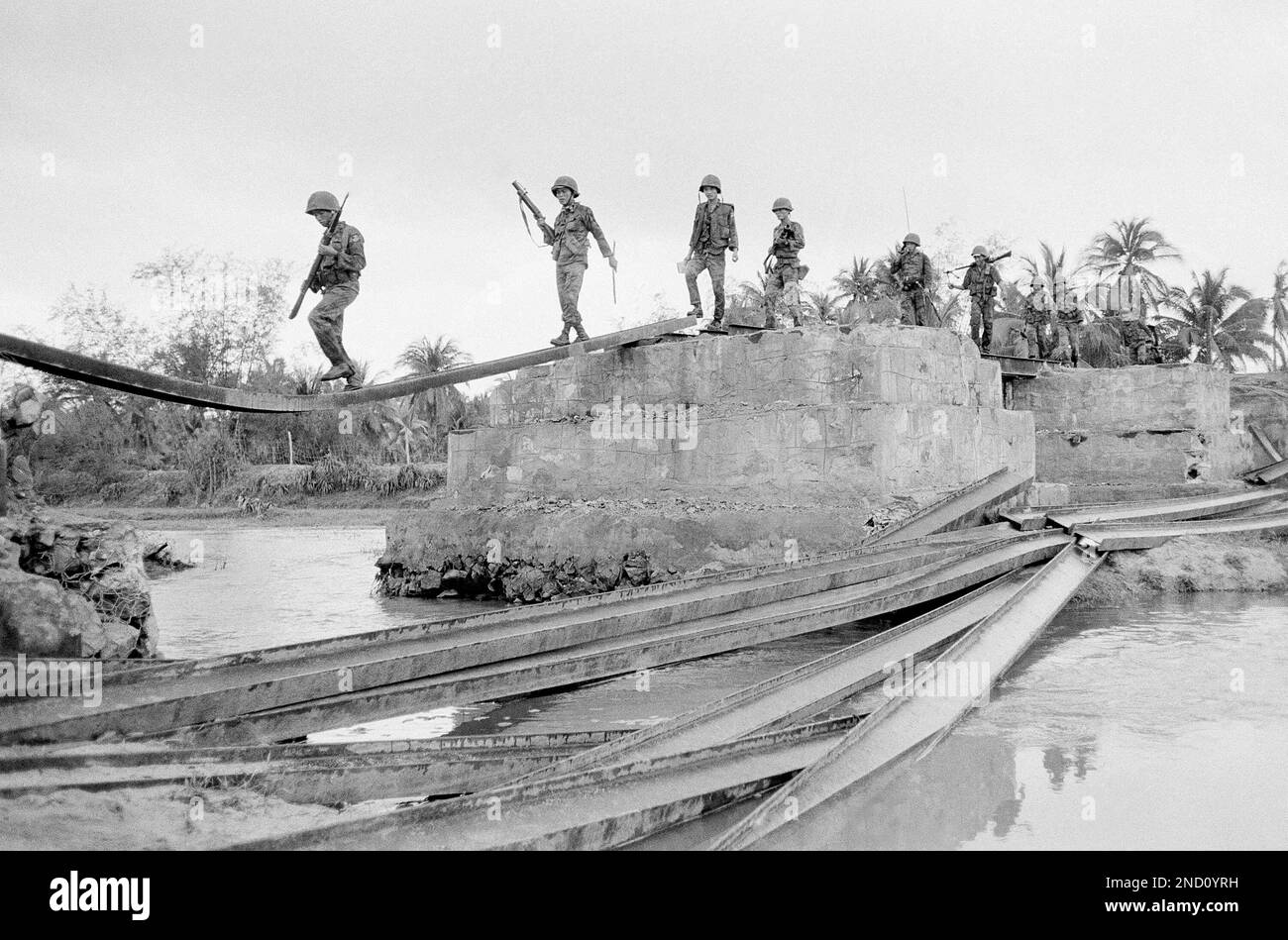 South Vietnamese marines walk a plank replacing blasted bridge near Qui ...