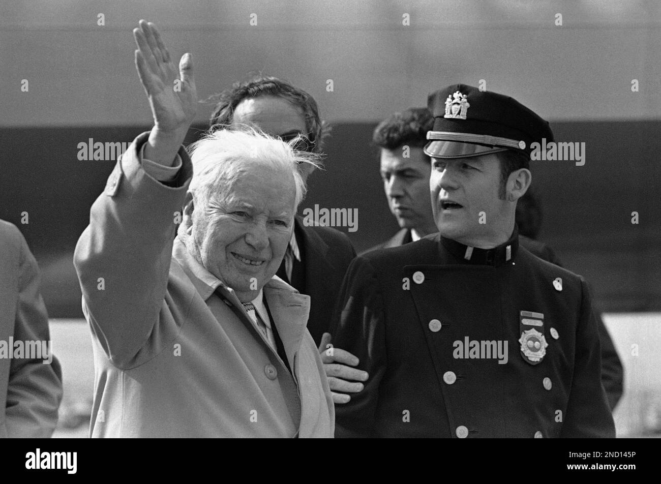 Comedian and film great Charlie Chaplin offers a smile and wave to fans ...
