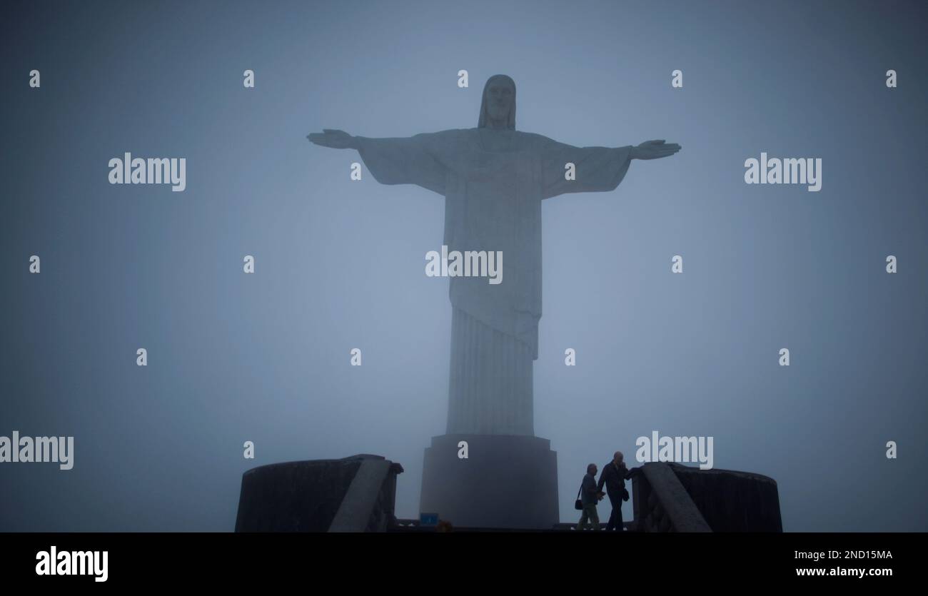 Tourists stand below the Christ the Redeemer statue in Rio de Janeiro ...