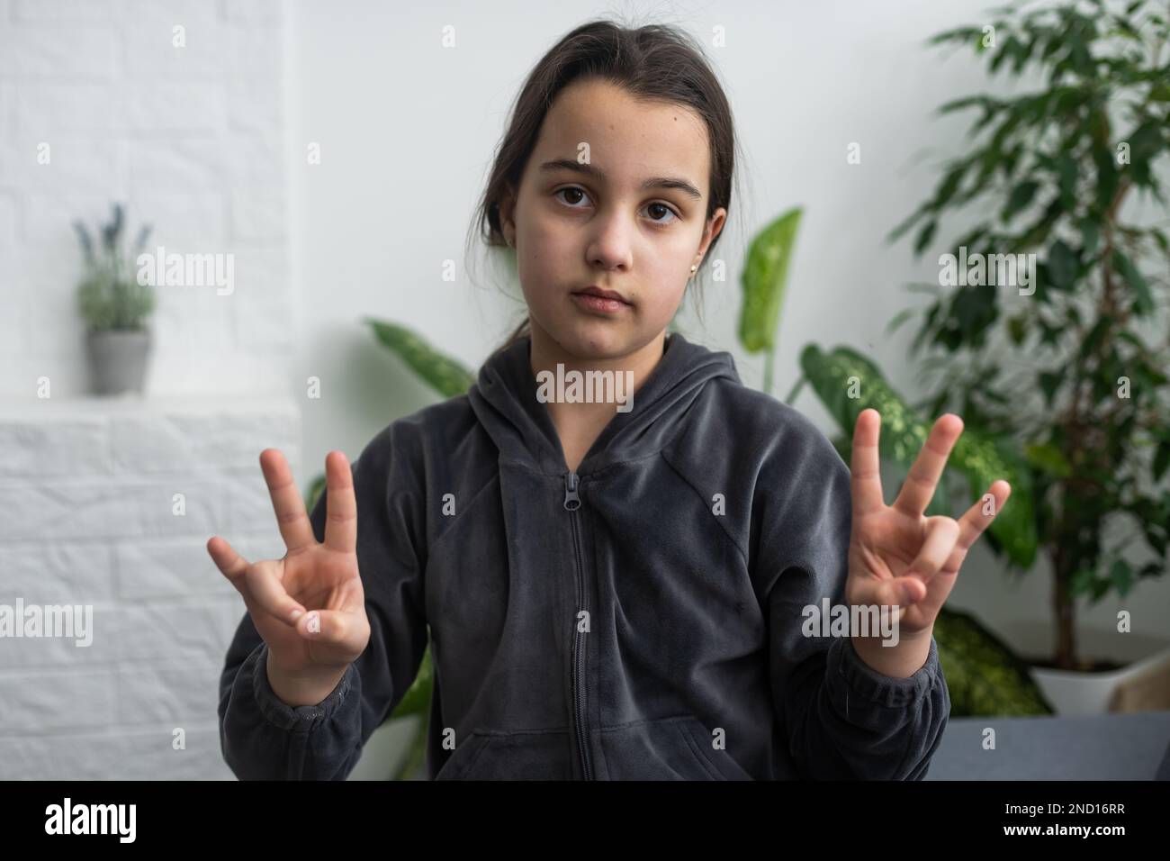 Cute deaf mute girl using sign language on light background Stock Photo ...