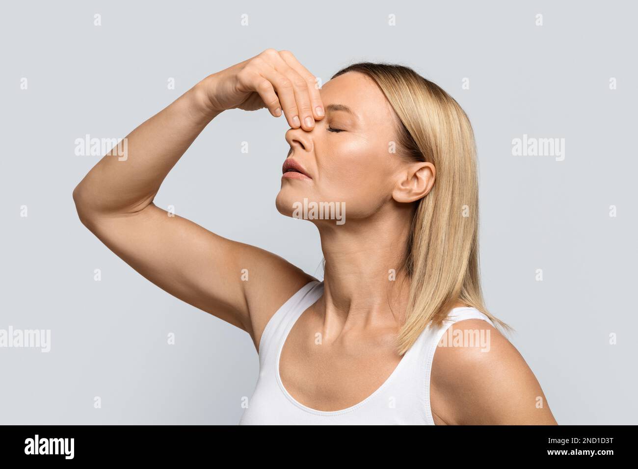Blonde woman touching nose, suffering from bleeding Stock Photo - Alamy