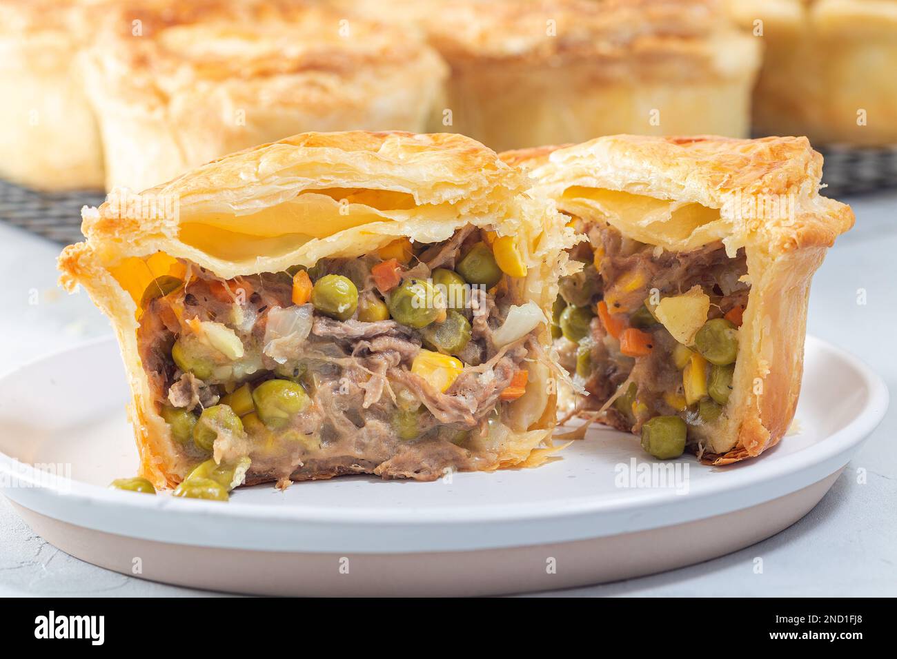 Sliced beef pot pie on plate, pies on a cooling rack, horizontal Stock ...