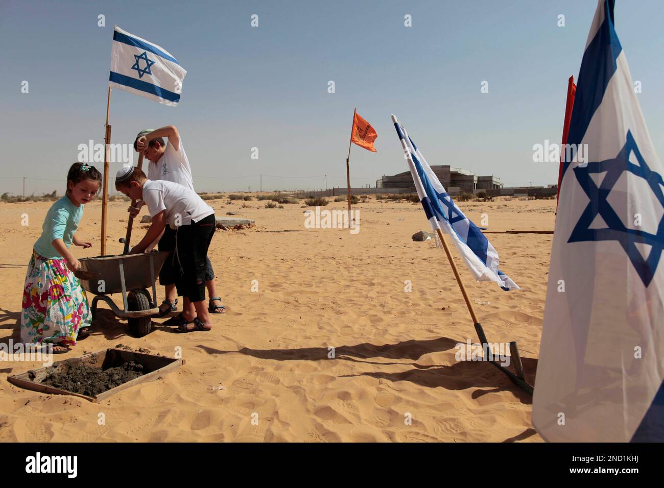 Israeli children play with cement after a cornerstone laying ceremony ...