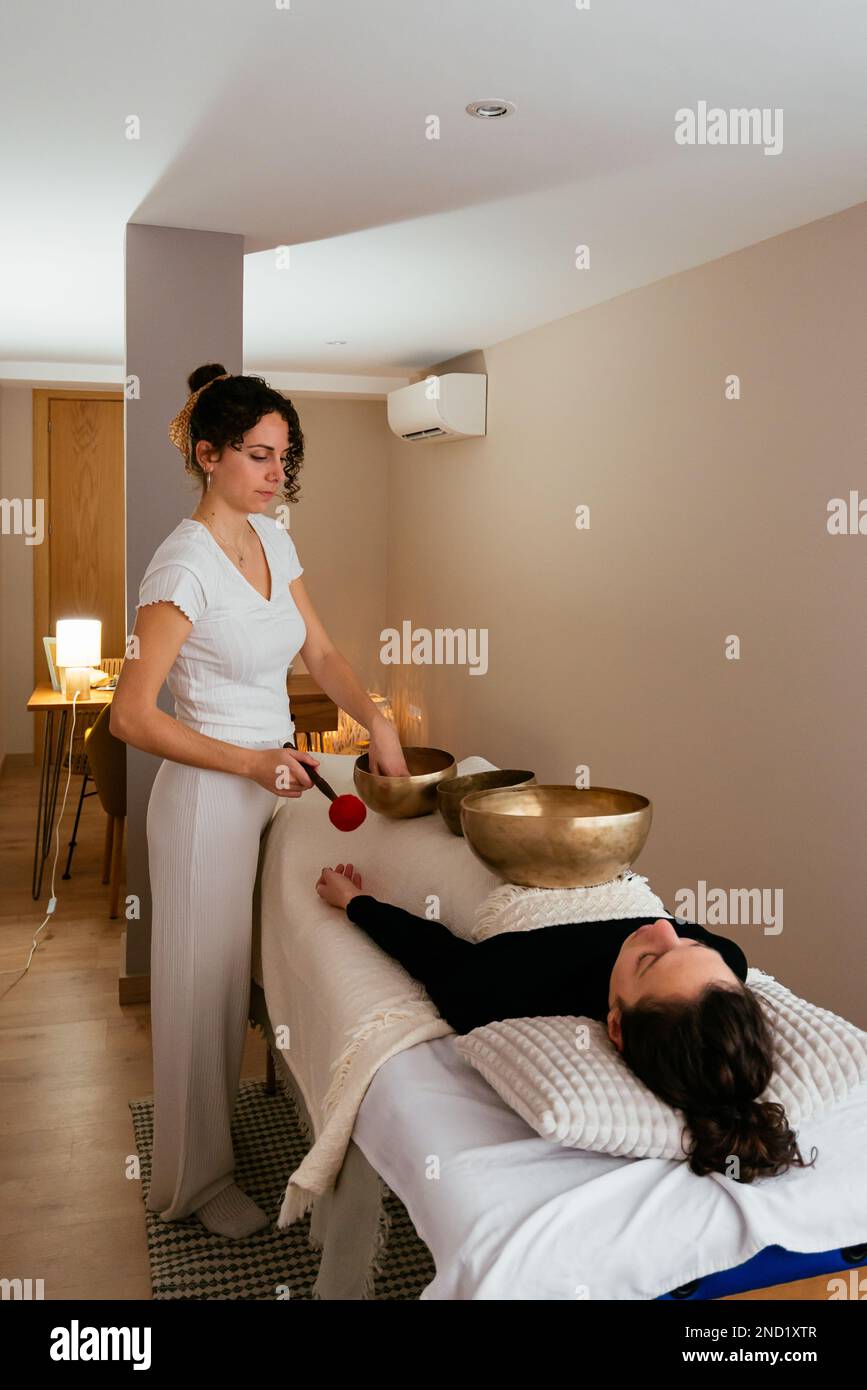 Concentrated female sound massage therapist in uniform standing near ...