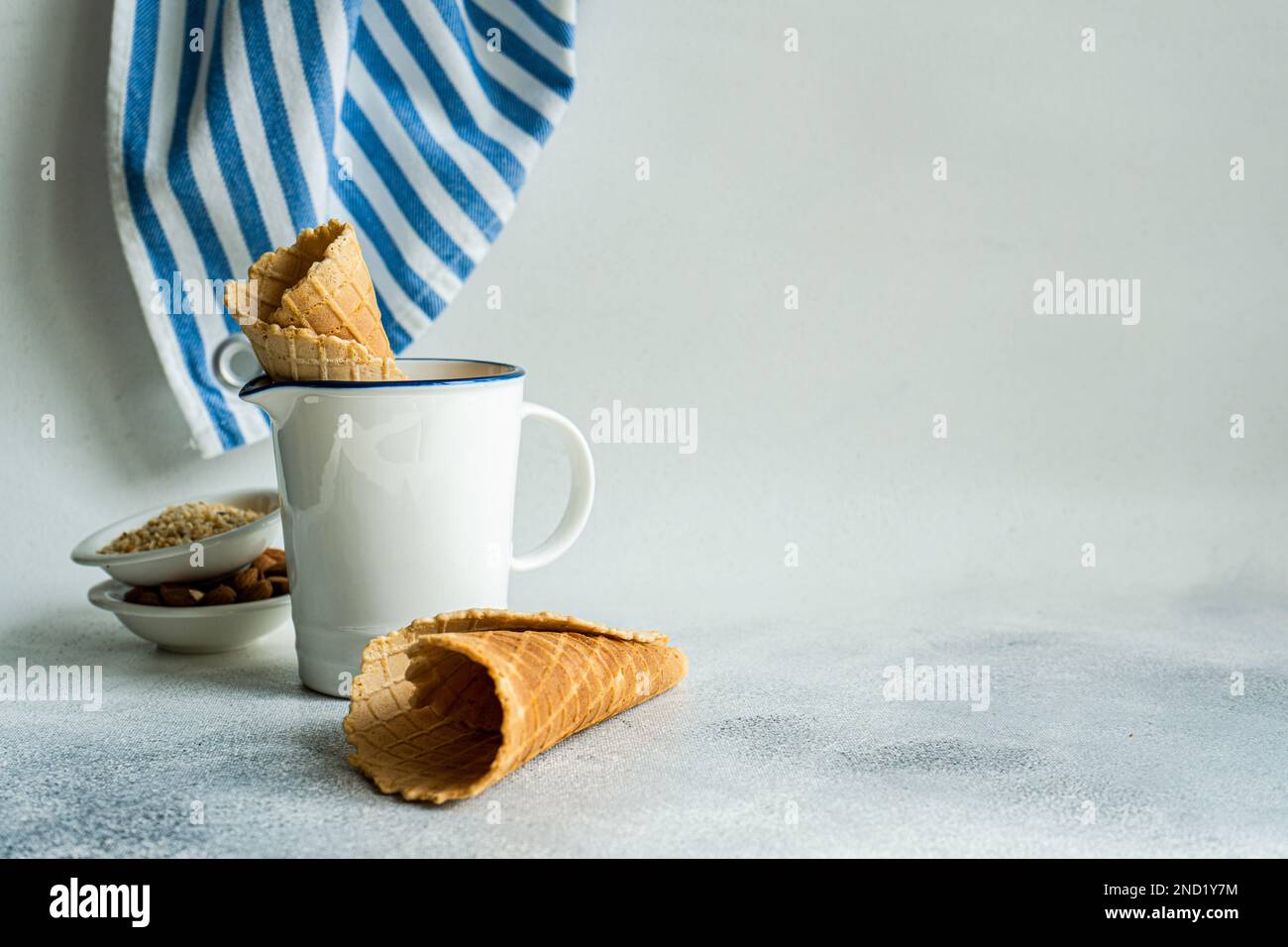 Waffle cones and nuts for ice cream preparation on concrete table with ...