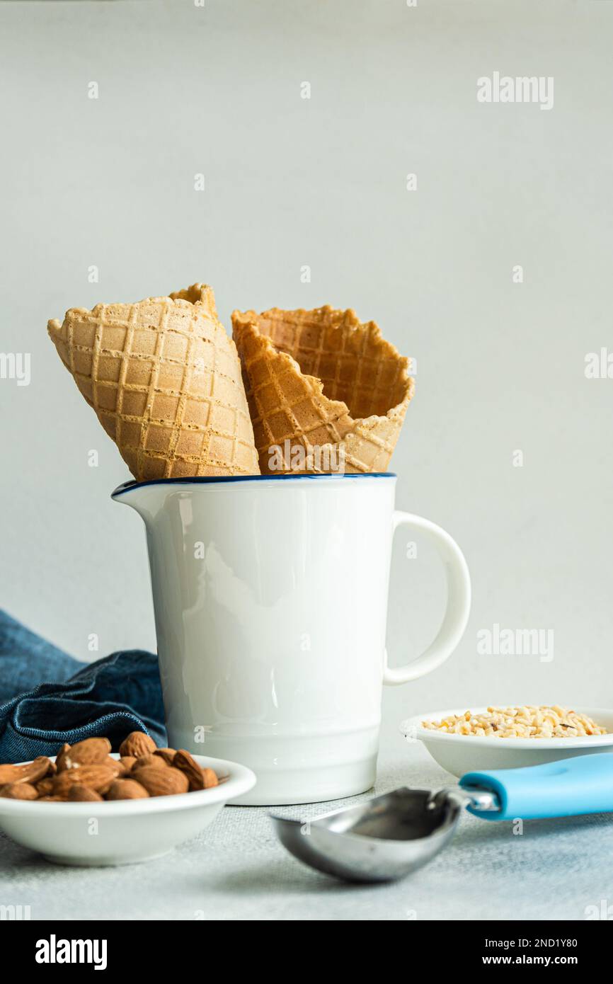 Waffle cones and nuts for ice cream preparation on concrete table with ...