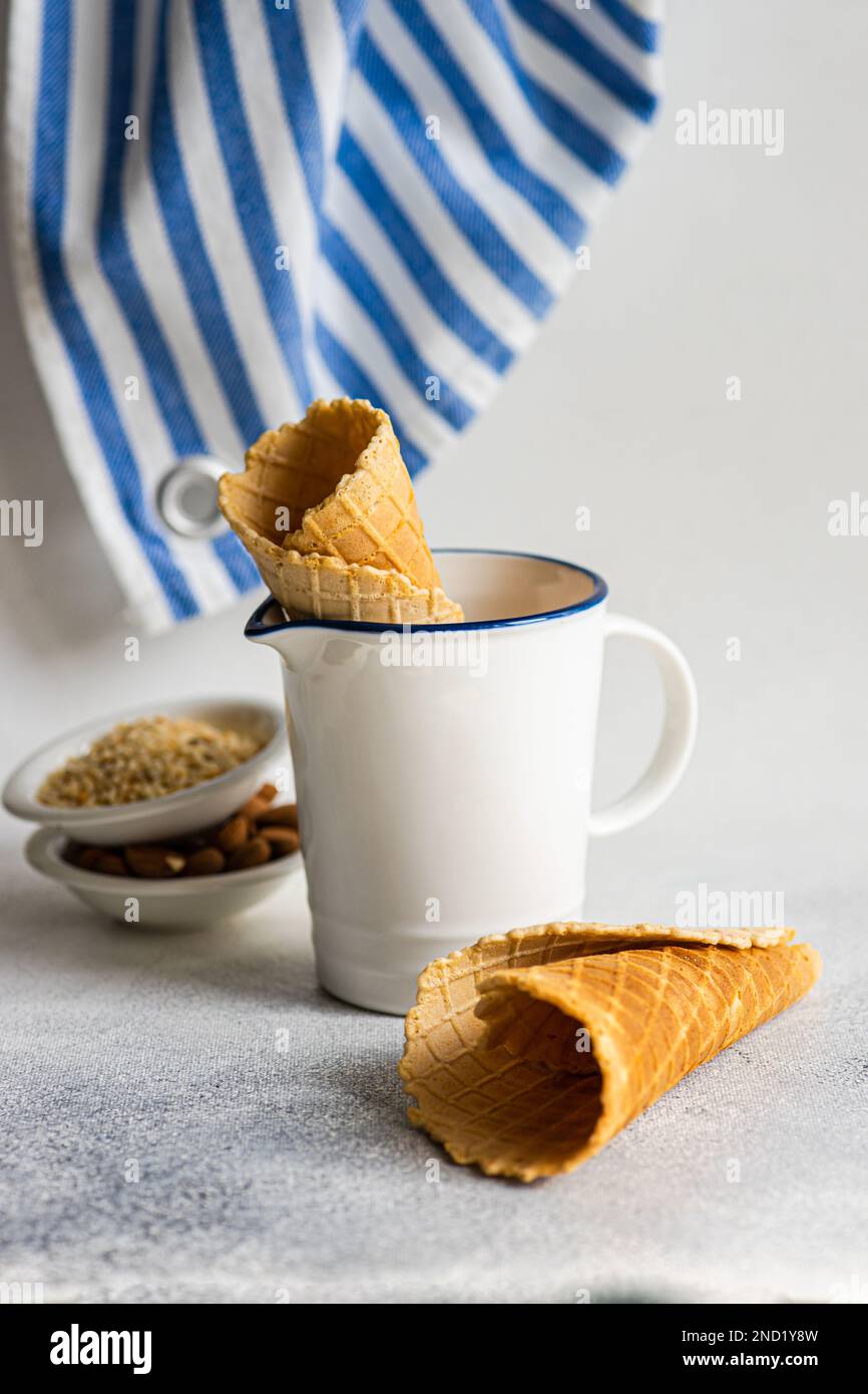 Waffle cones and nuts for ice cream preparation on concrete table with ...