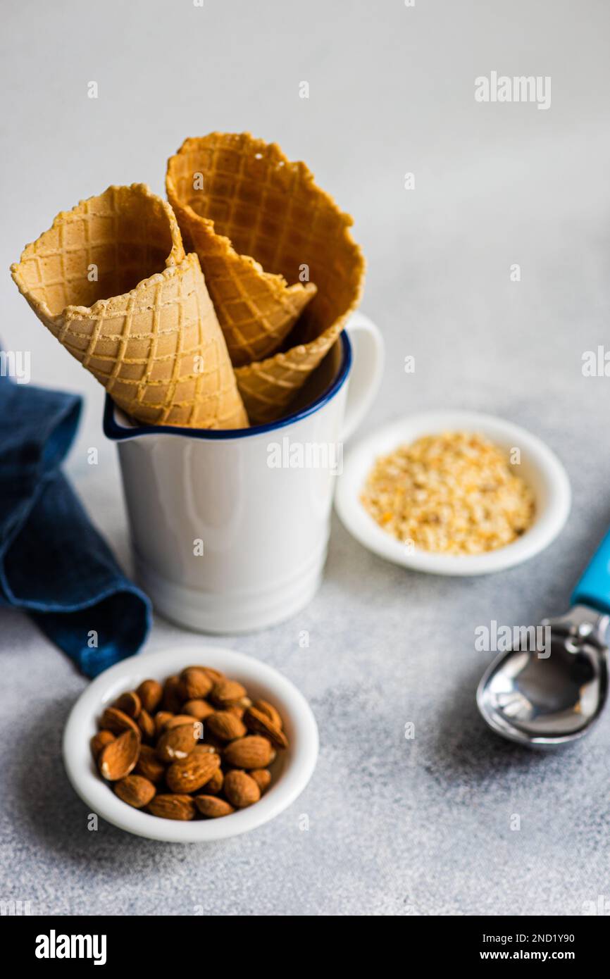 Waffle cones and nuts for ice cream preparation on concrete table with ...