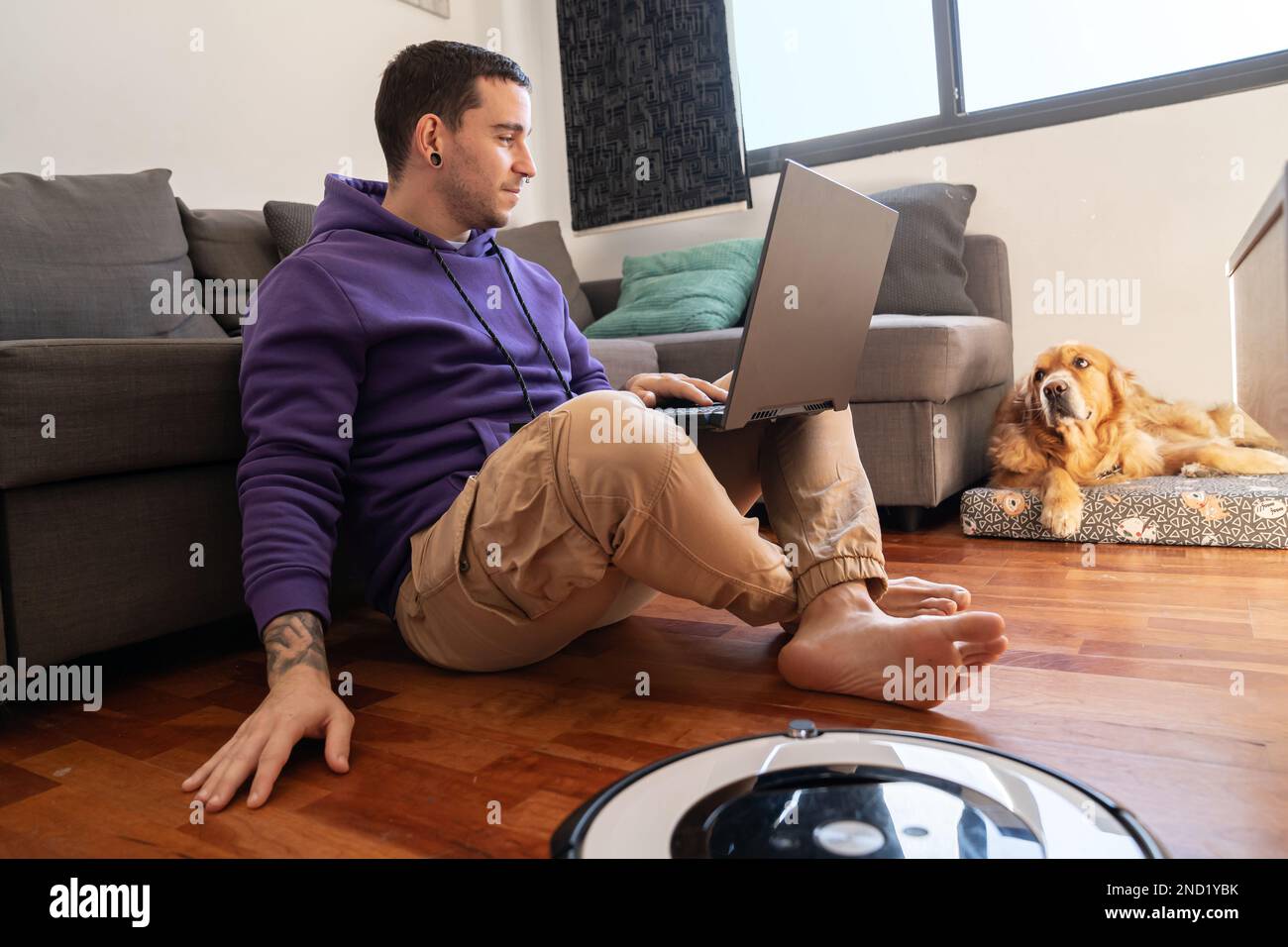 Full body of concentrated male freelancer working on laptop while ...